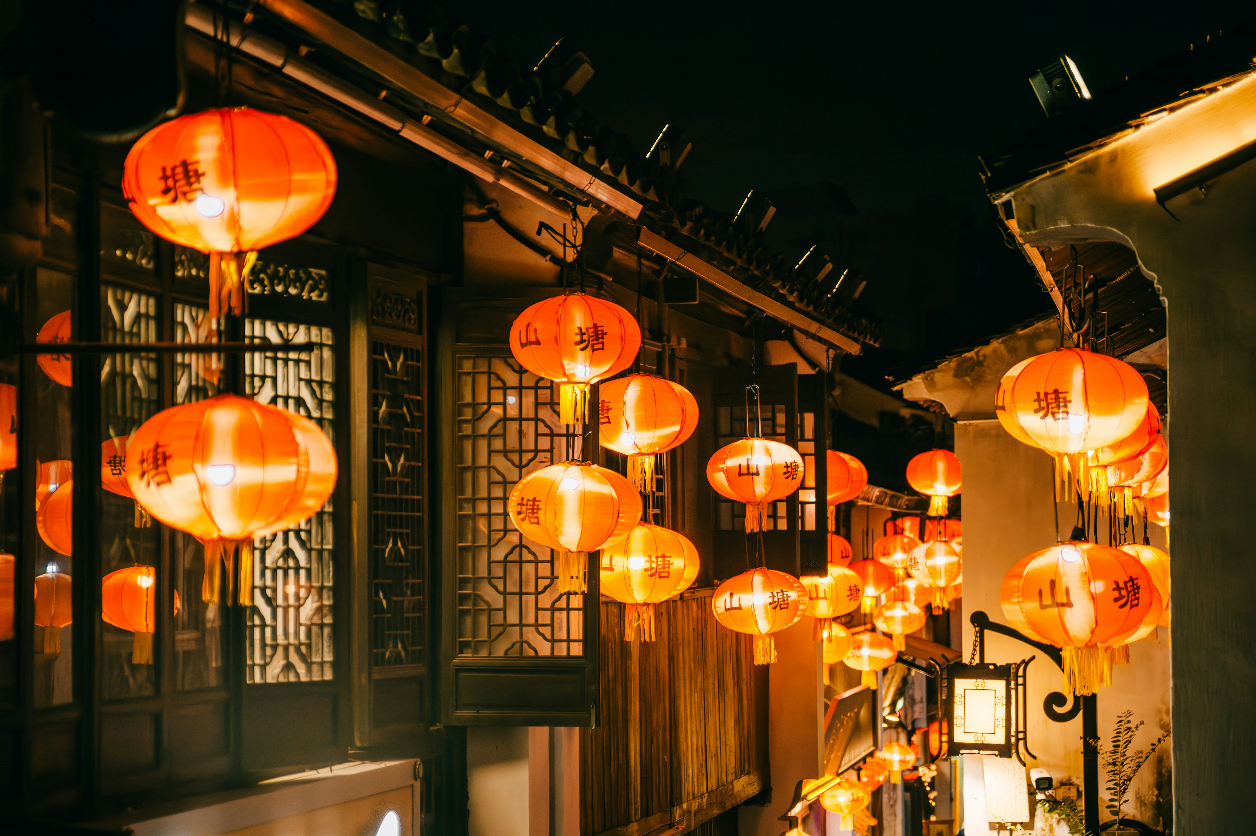 A narrow street with lots of red lanterns hanging from the ceiling ...