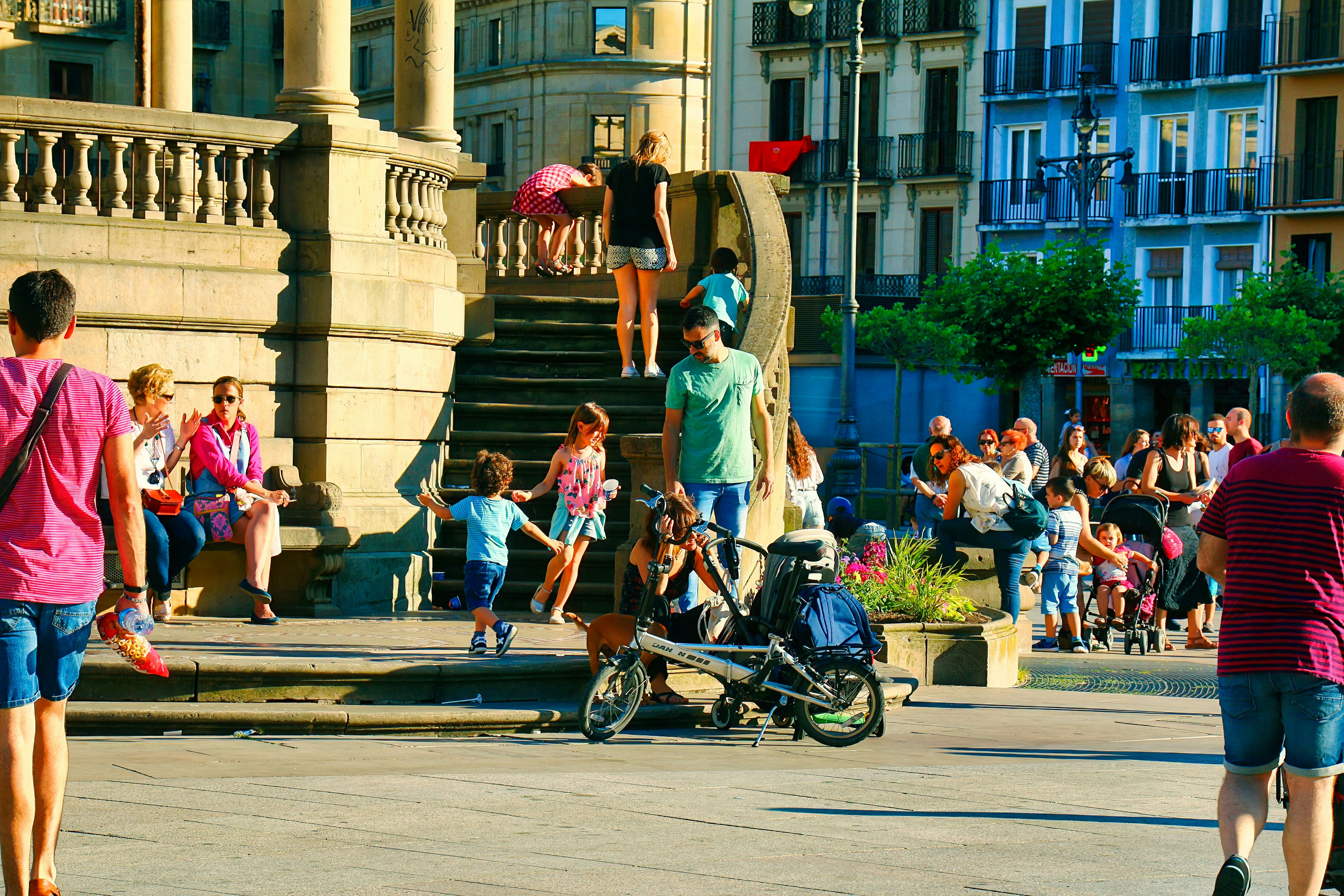 A group of people walking around a city square photo – Free Pamplona ...