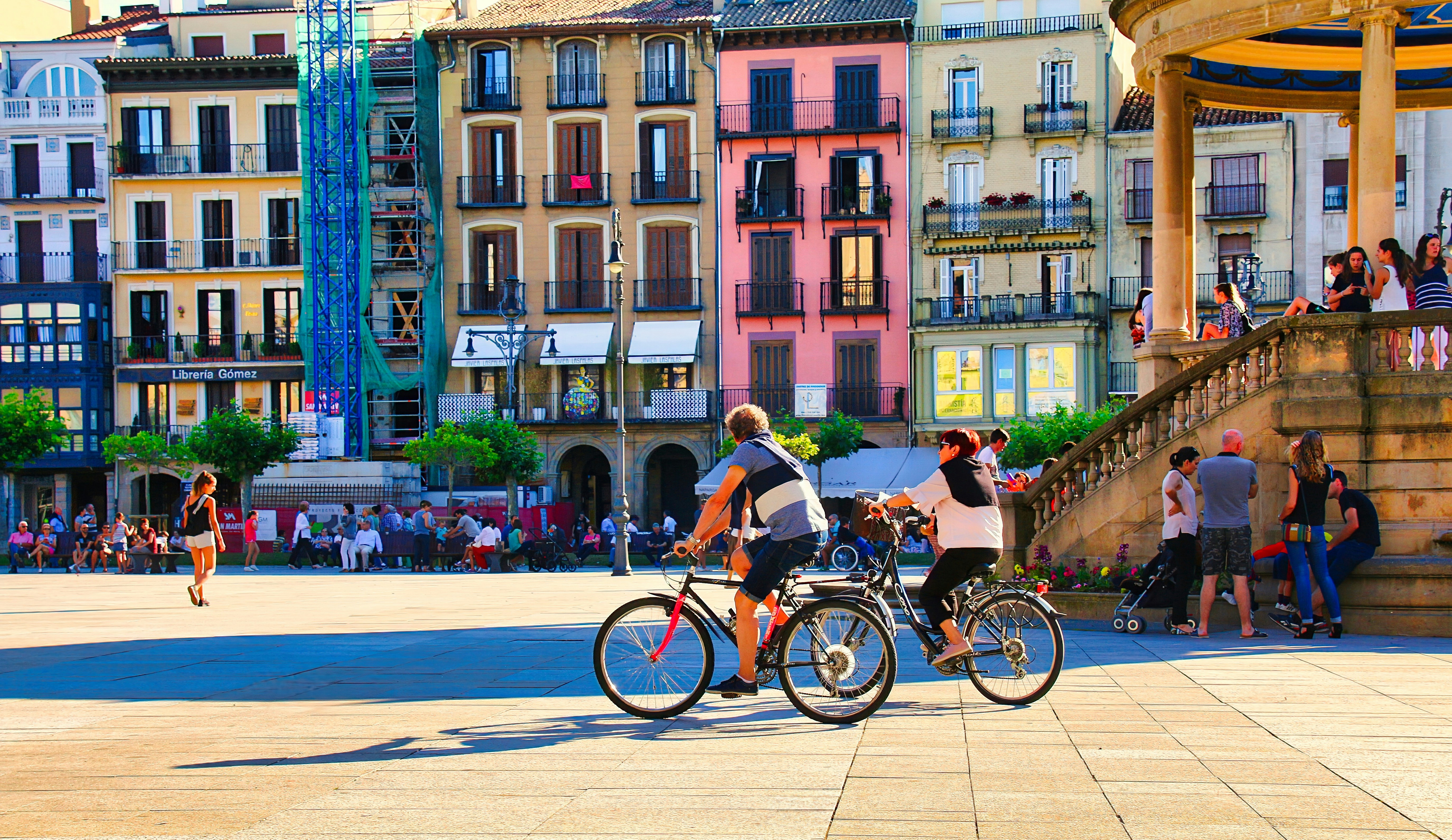 Cyclists in a Sunlit Spanish-style Plaza