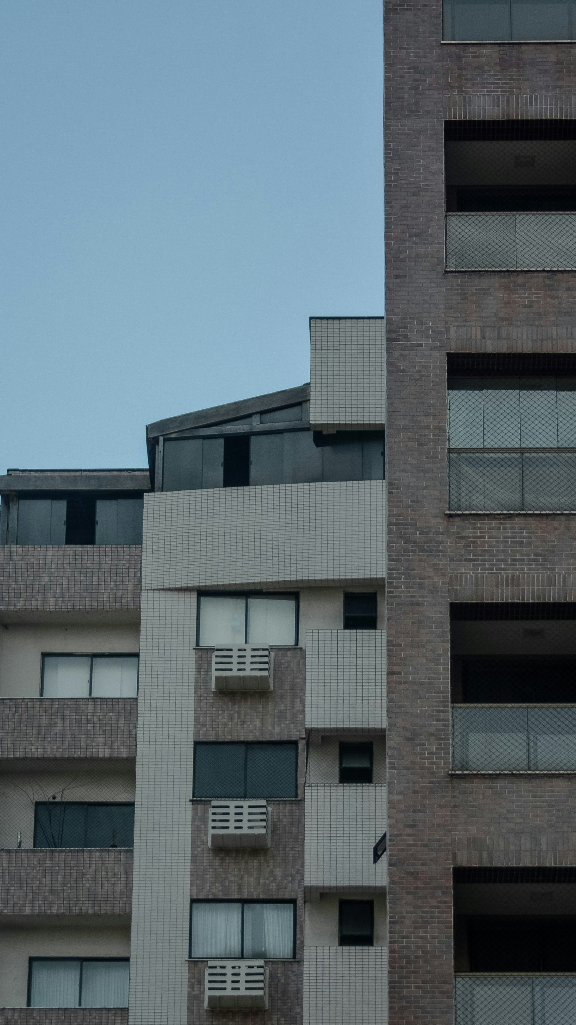 Close-up of modern high-rise buildings with varied textures and window placements against a clear sky.