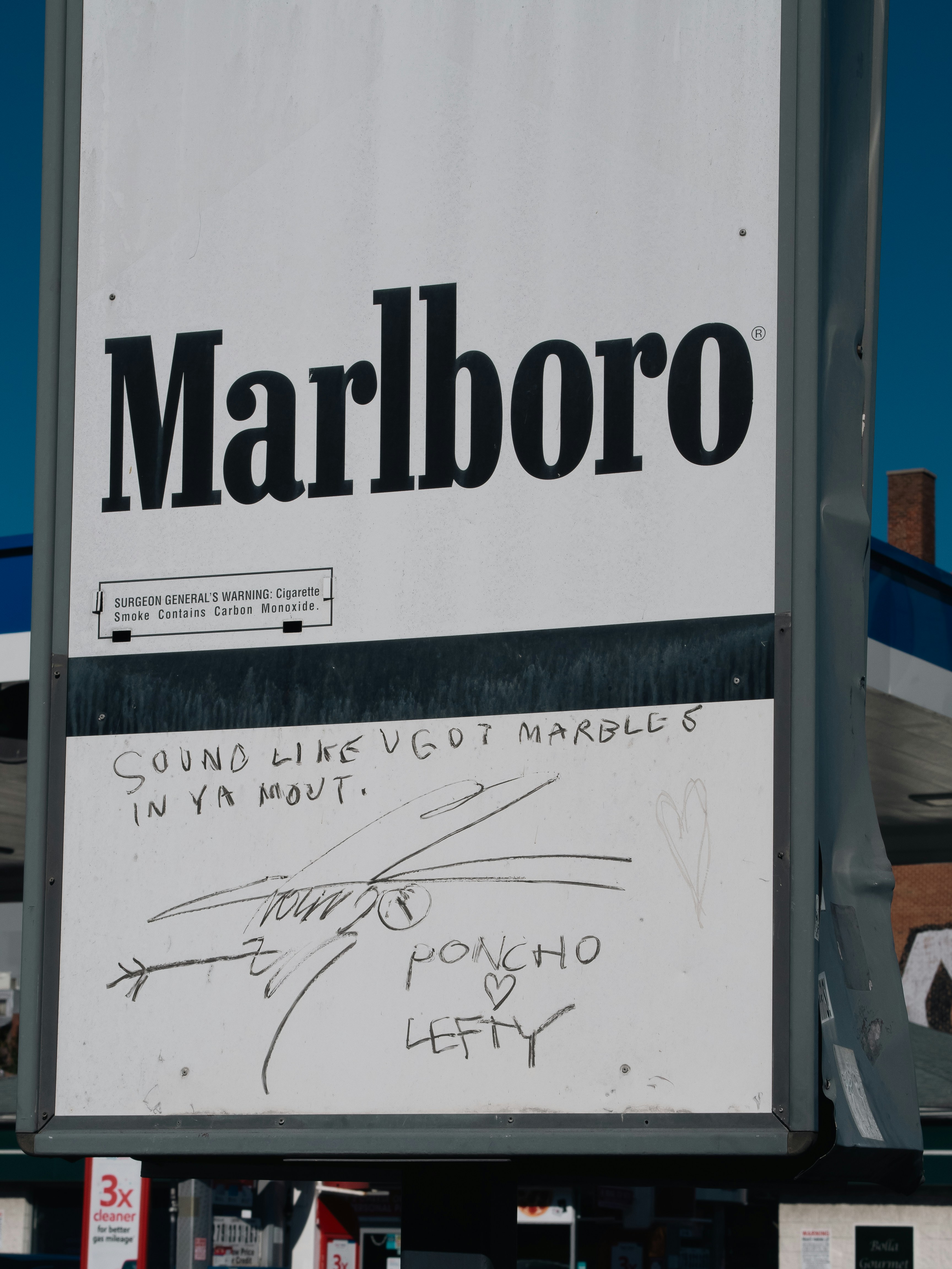 Marlboro logo on a roadside billboard dominates the frame. The lower panel shows graffiti and rough sketches.