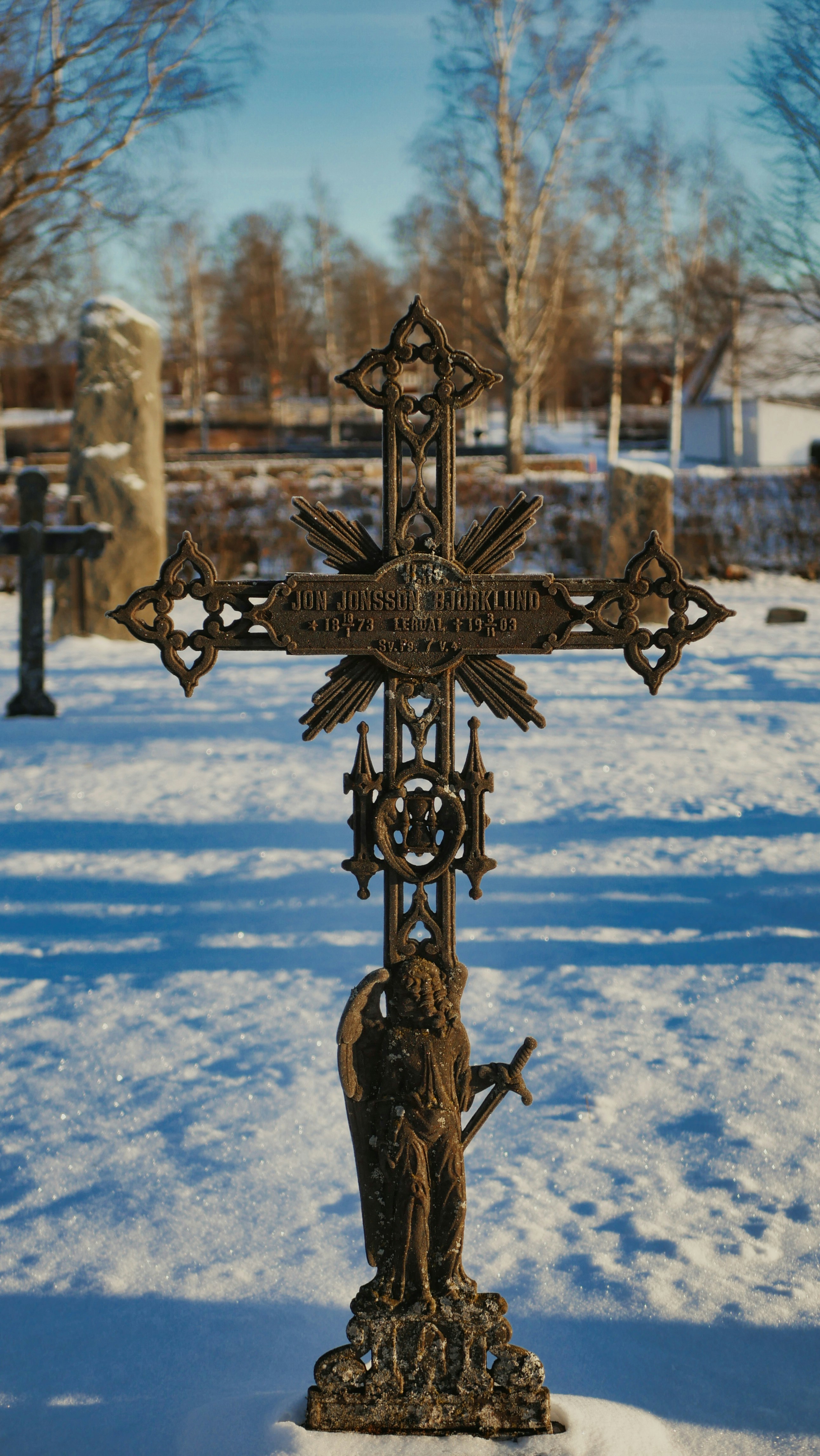 Snowlit Iron Cross: ornate grave marker in a quiet cemetery