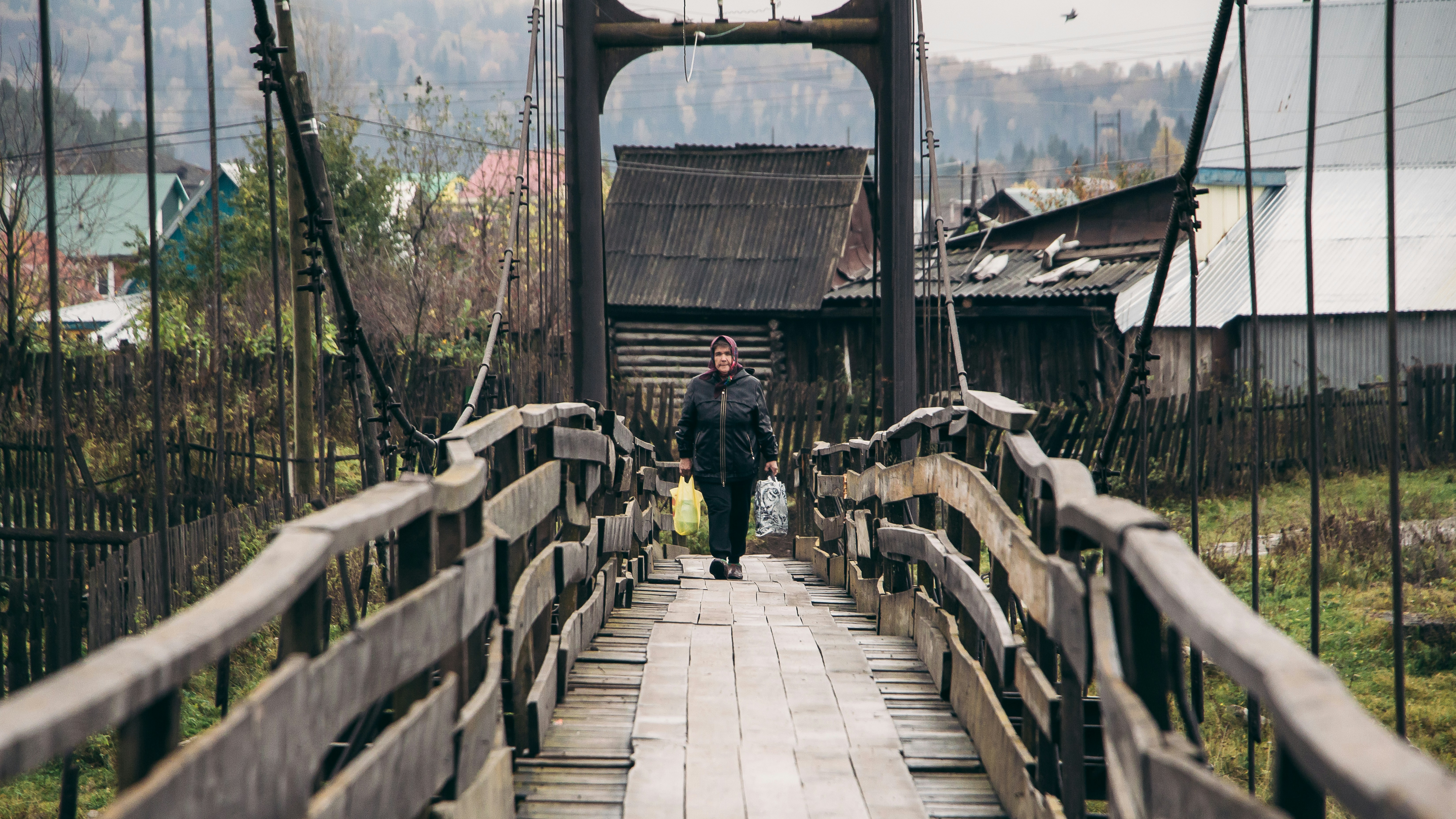 Midspan Walk: A solitary figure on a weathered suspension bridge