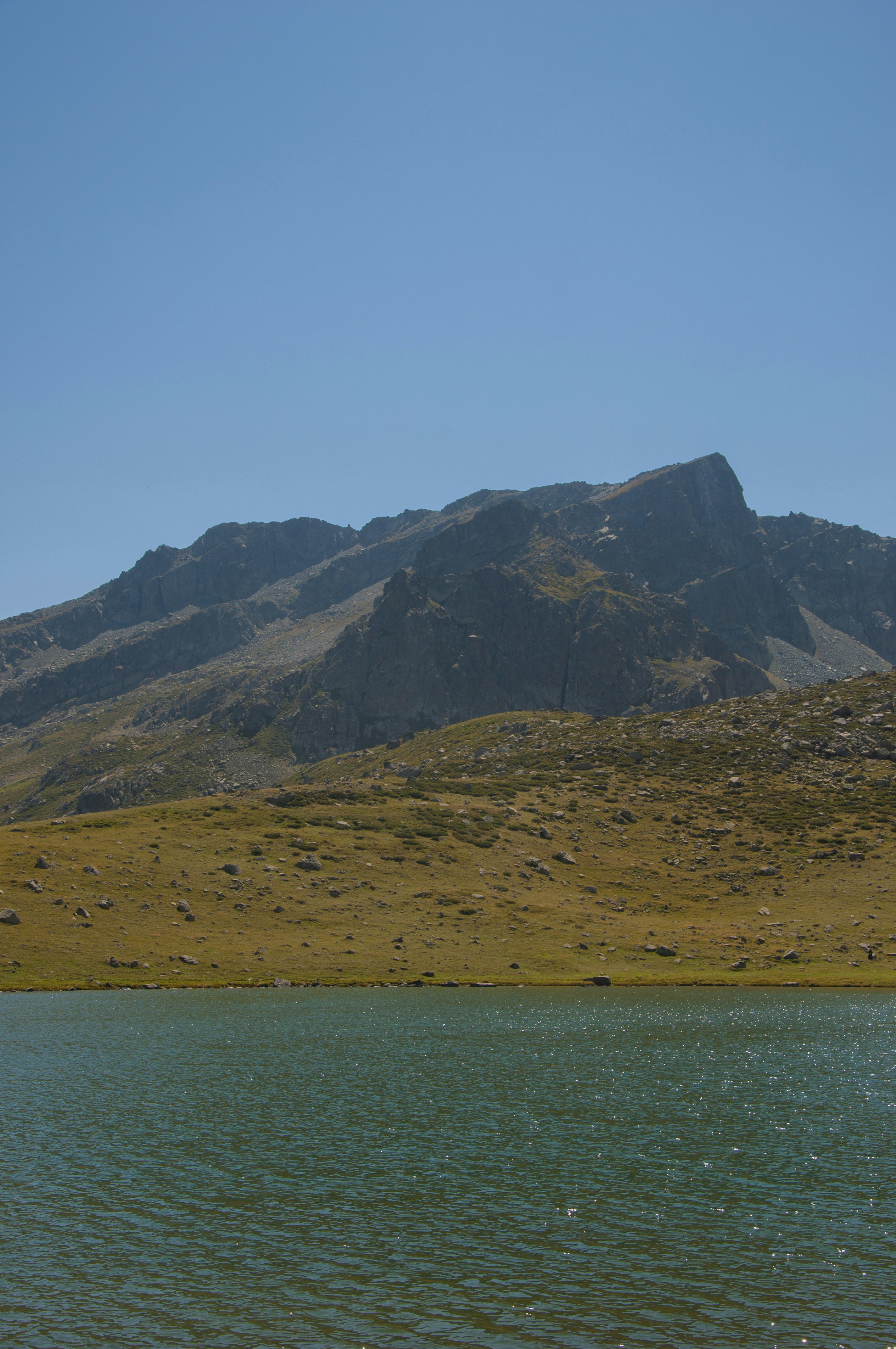 Granite Ridge Under a Clear Alpine Sky Over a Tranquil Lake
