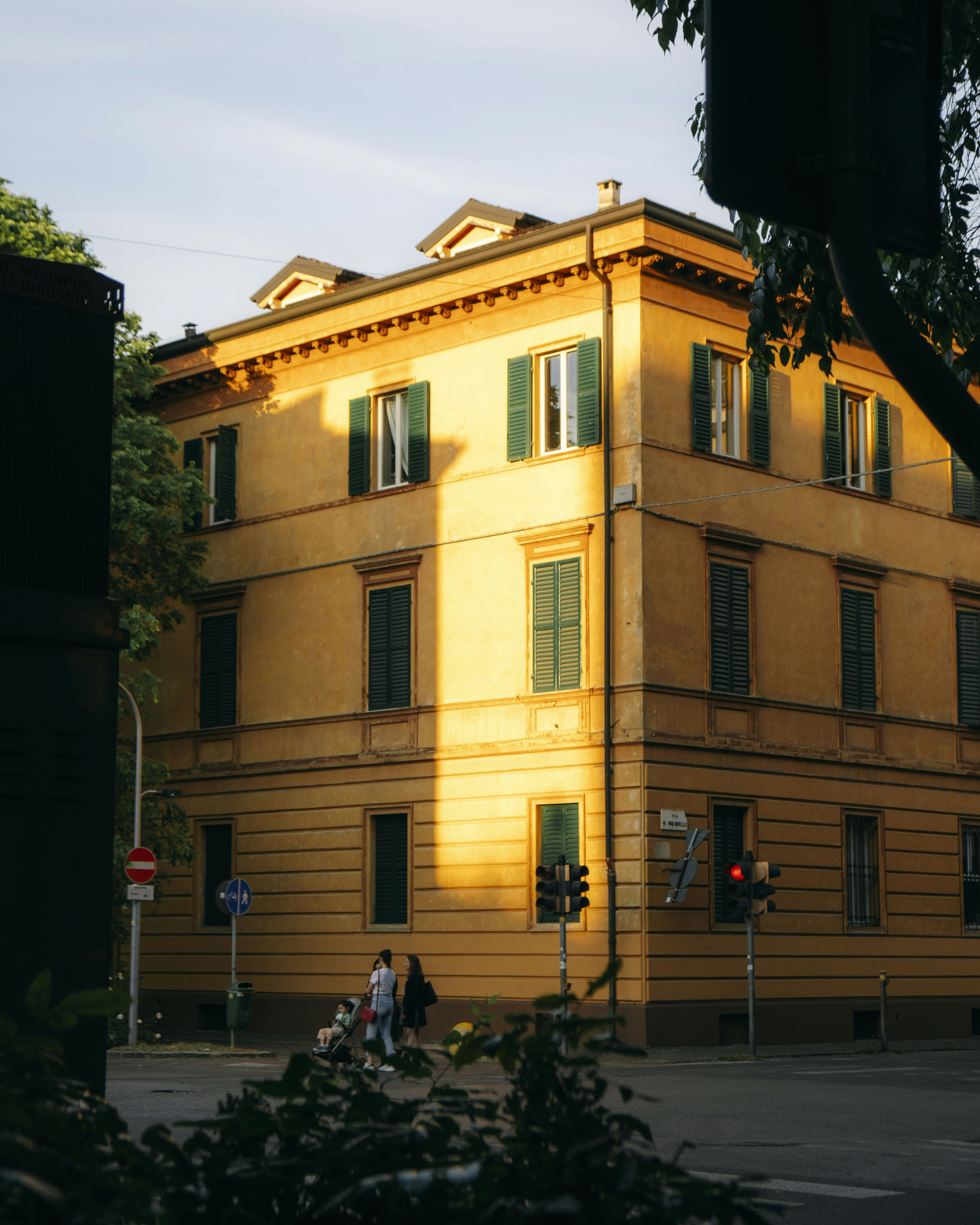 A yellow building with green shutters on a street corner photo – Free ...
