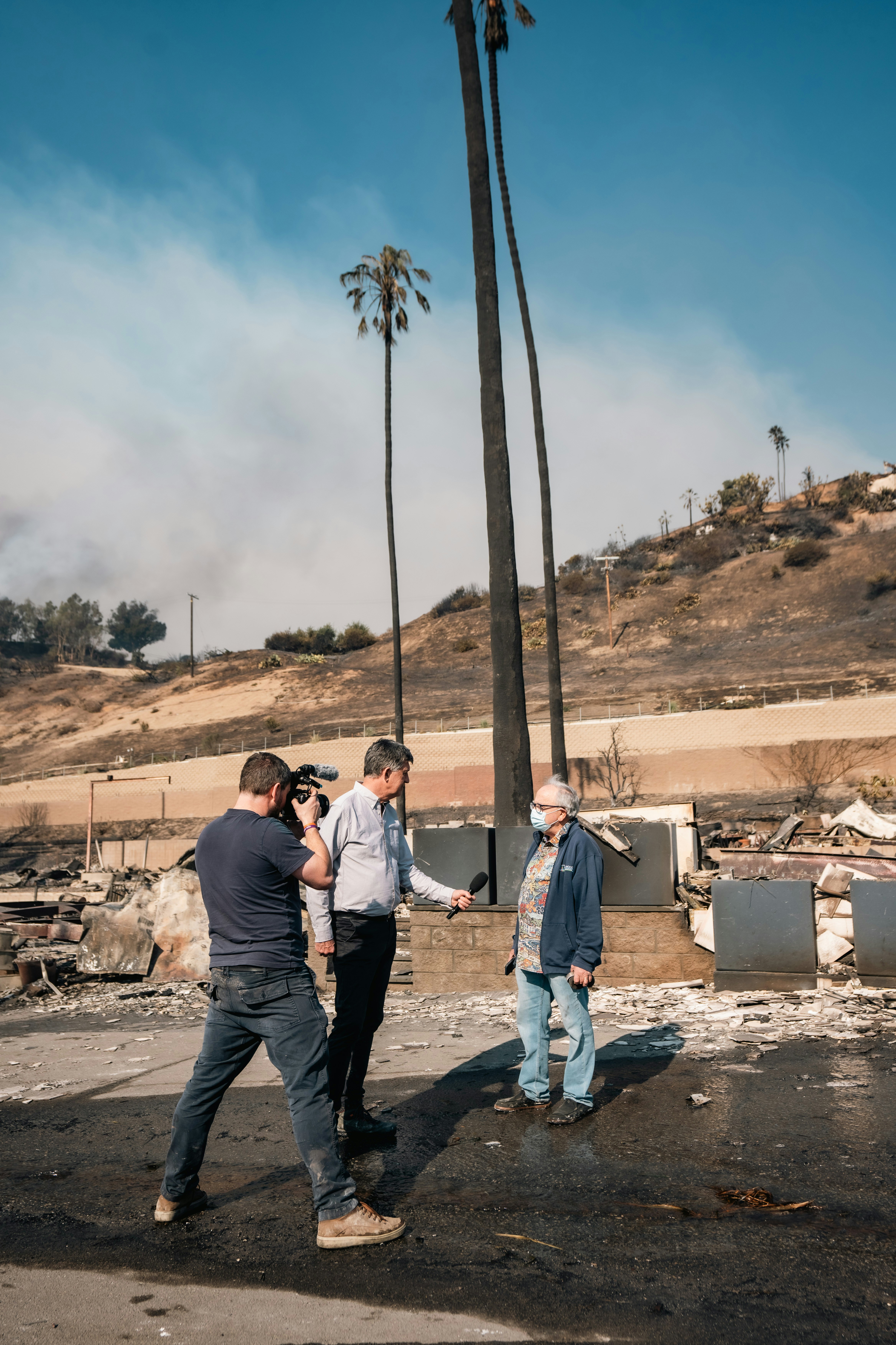 Reporting in a Charred Lot Beneath Palm Shadows