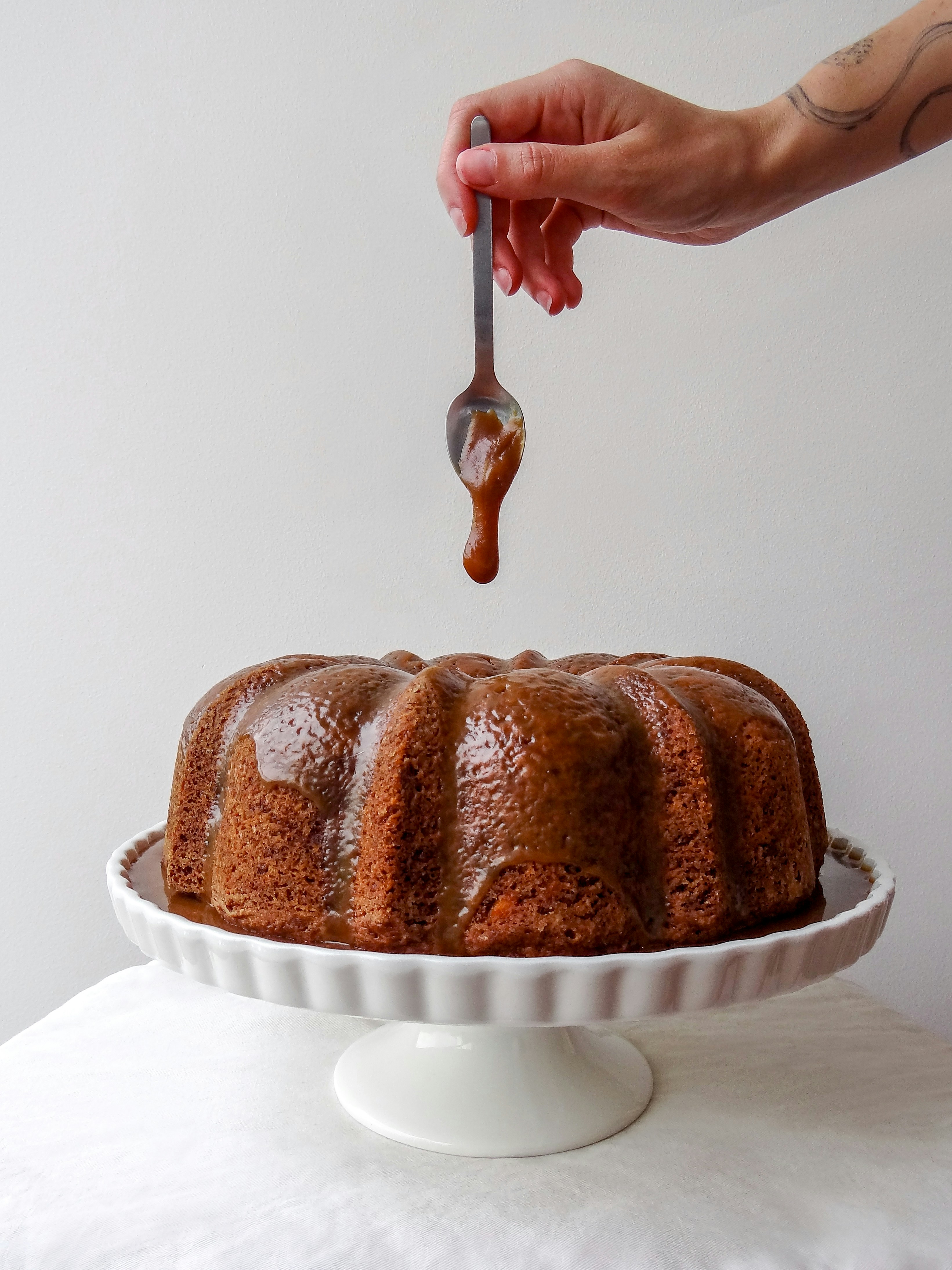 A person is spreading icing on a bundt cake photo – Free Food ...