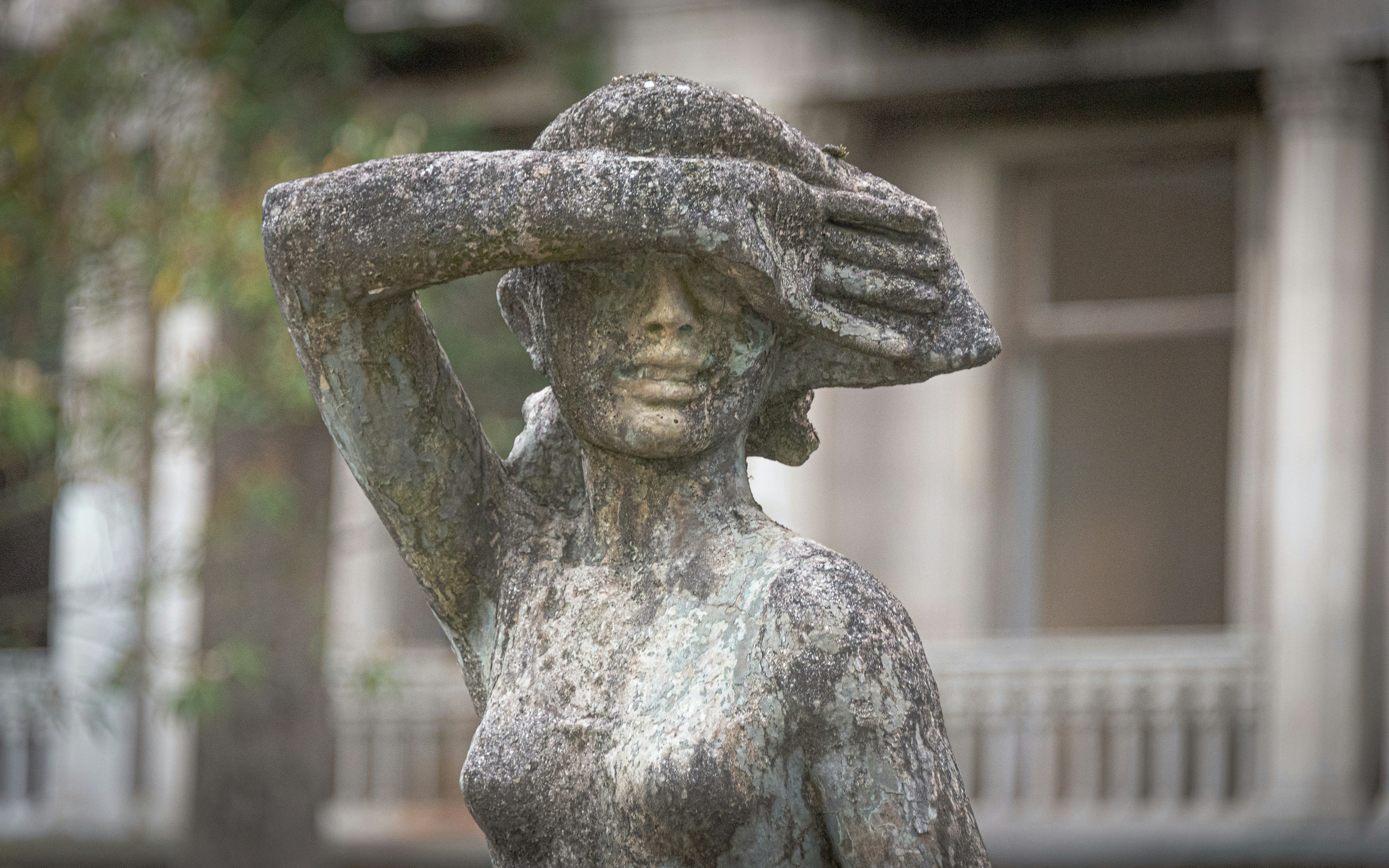Shielded Gaze: Weathered Statue in a Quiet Courtyard