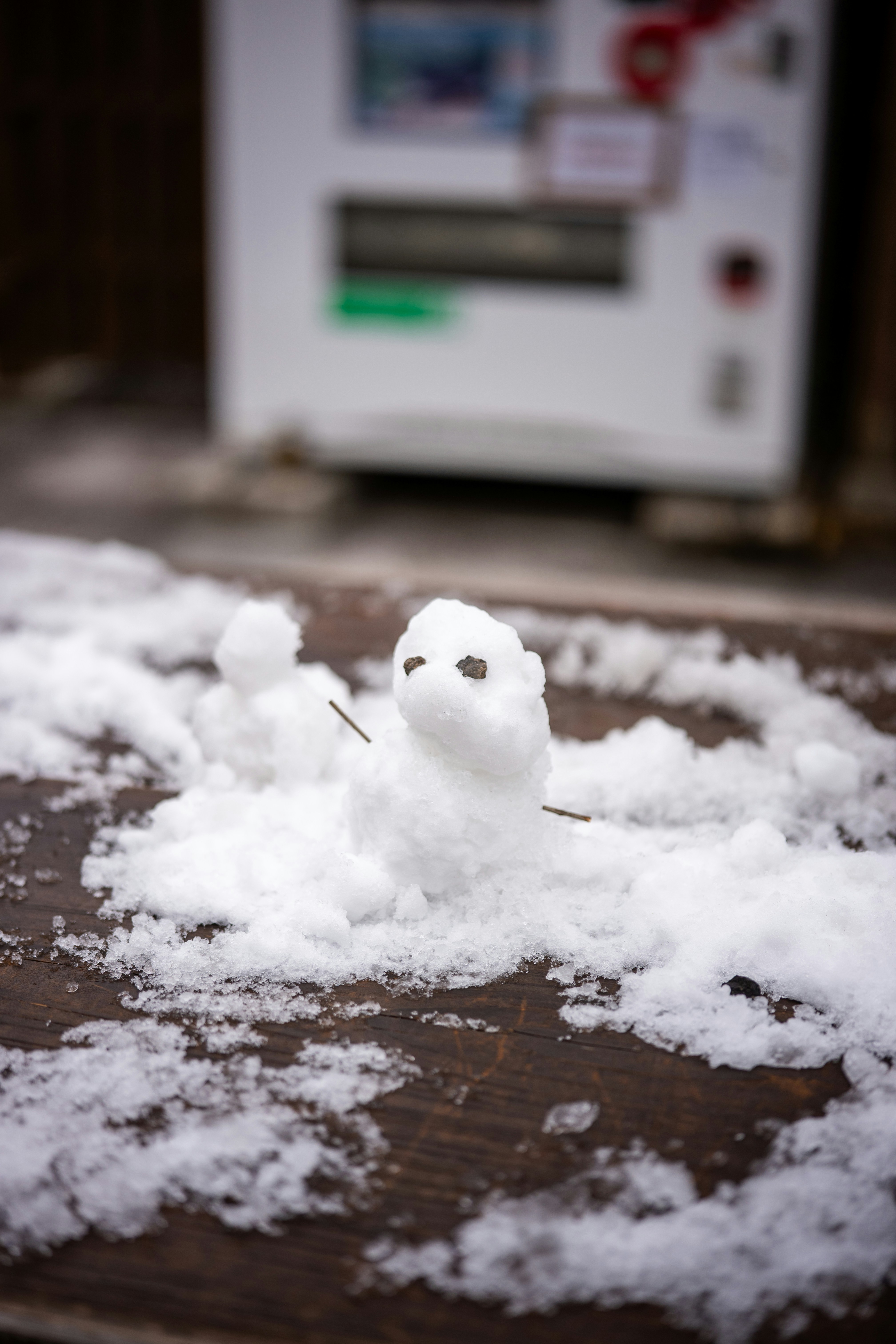 Tiny Snowman on a Weathered Deck, with a Softly Blurred Industrial Backdrop