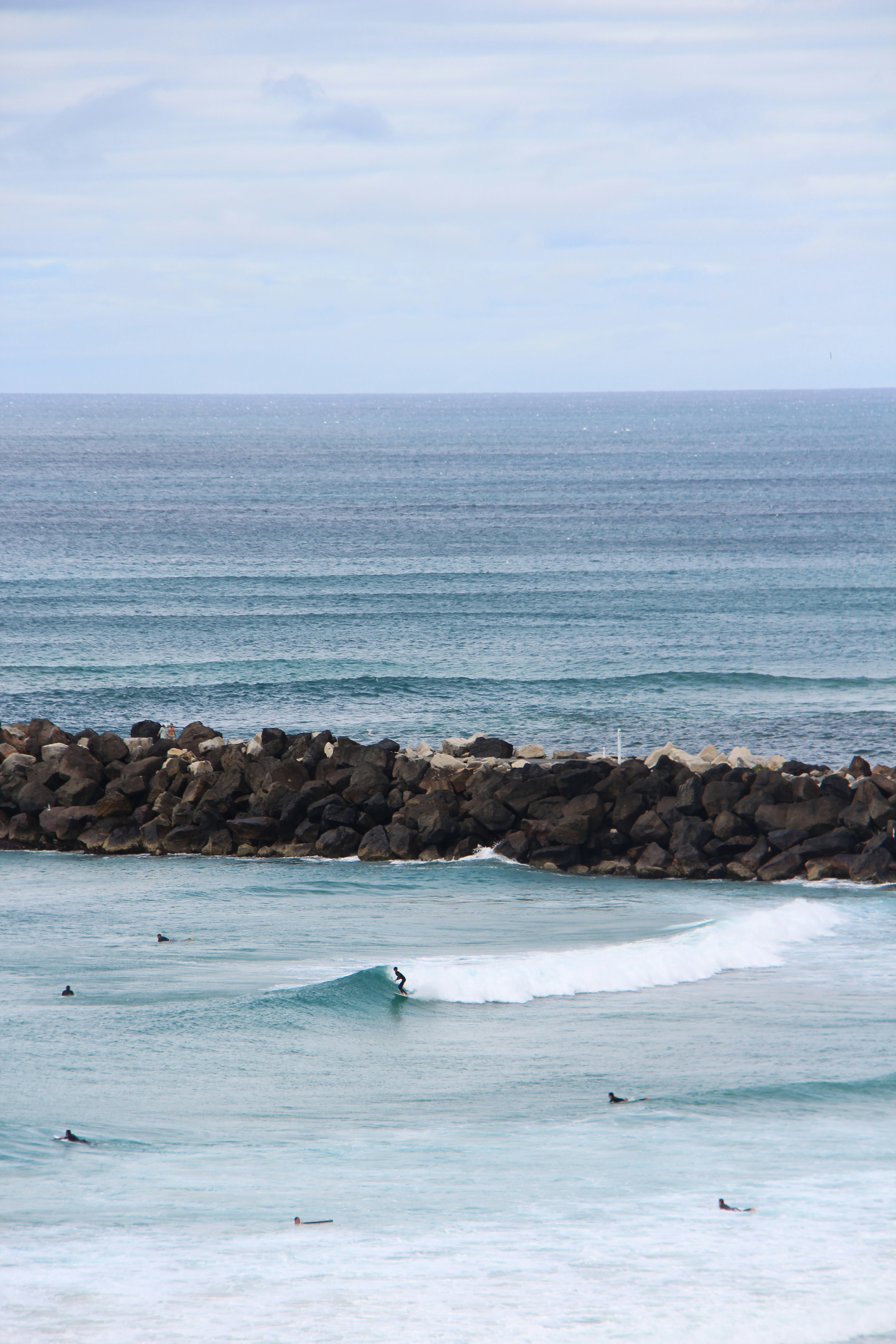 A group of surfers riding waves in the ocean photo – Free Beach Image ...