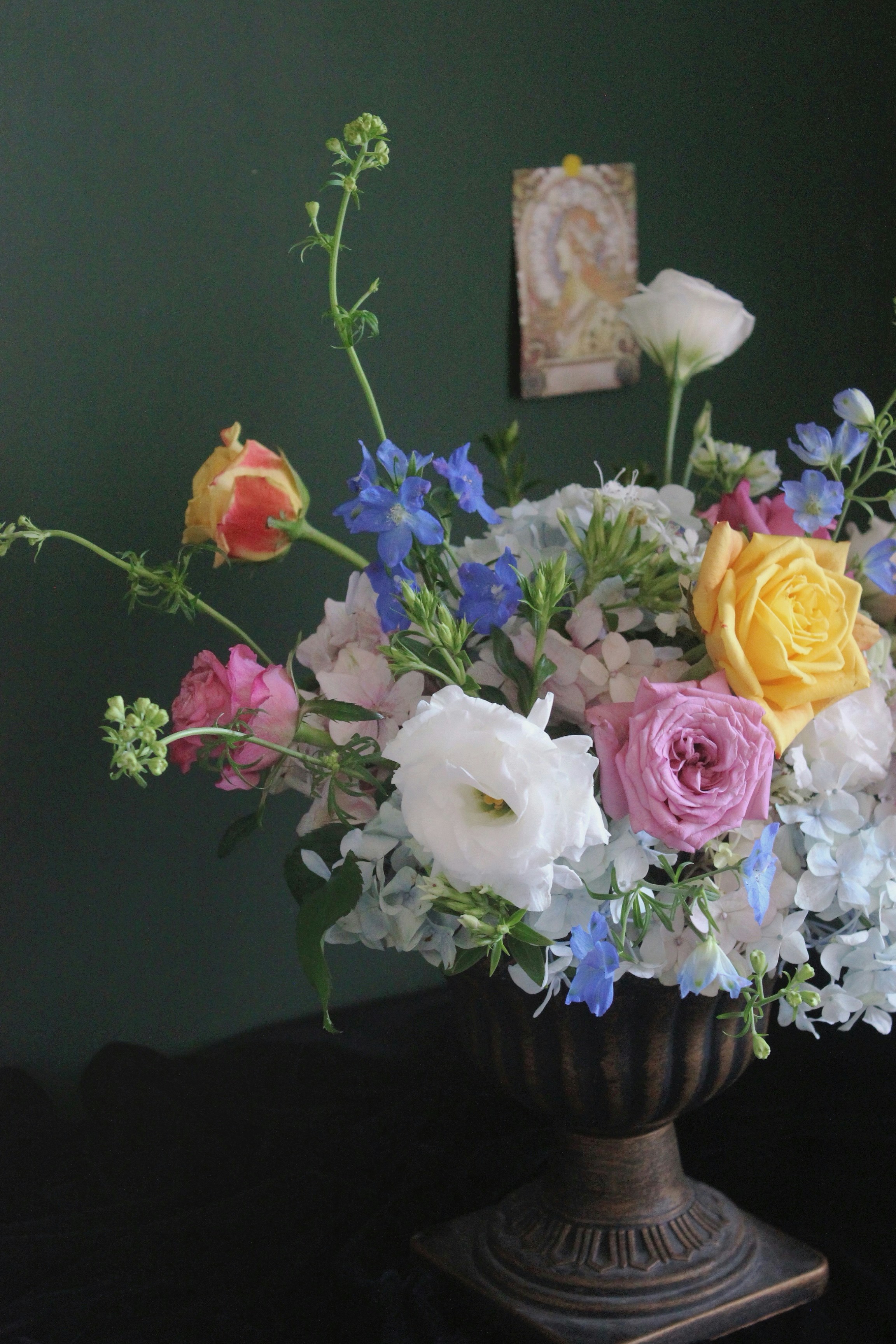 Bouquet in bronze pedestal: a colorful still life against a deep green backdrop