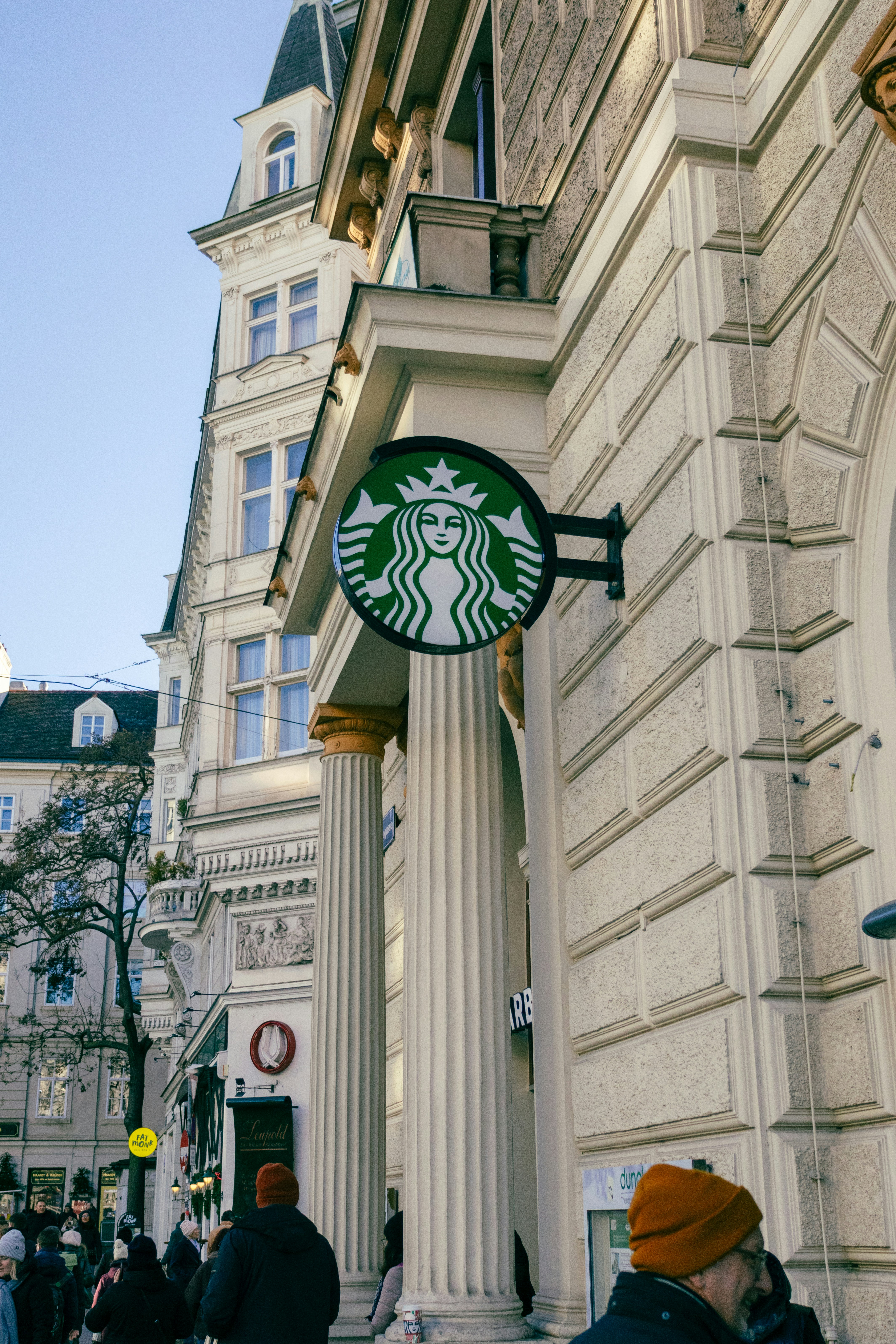 A starbucks sign hanging from the side of a building photo – Free City ...
