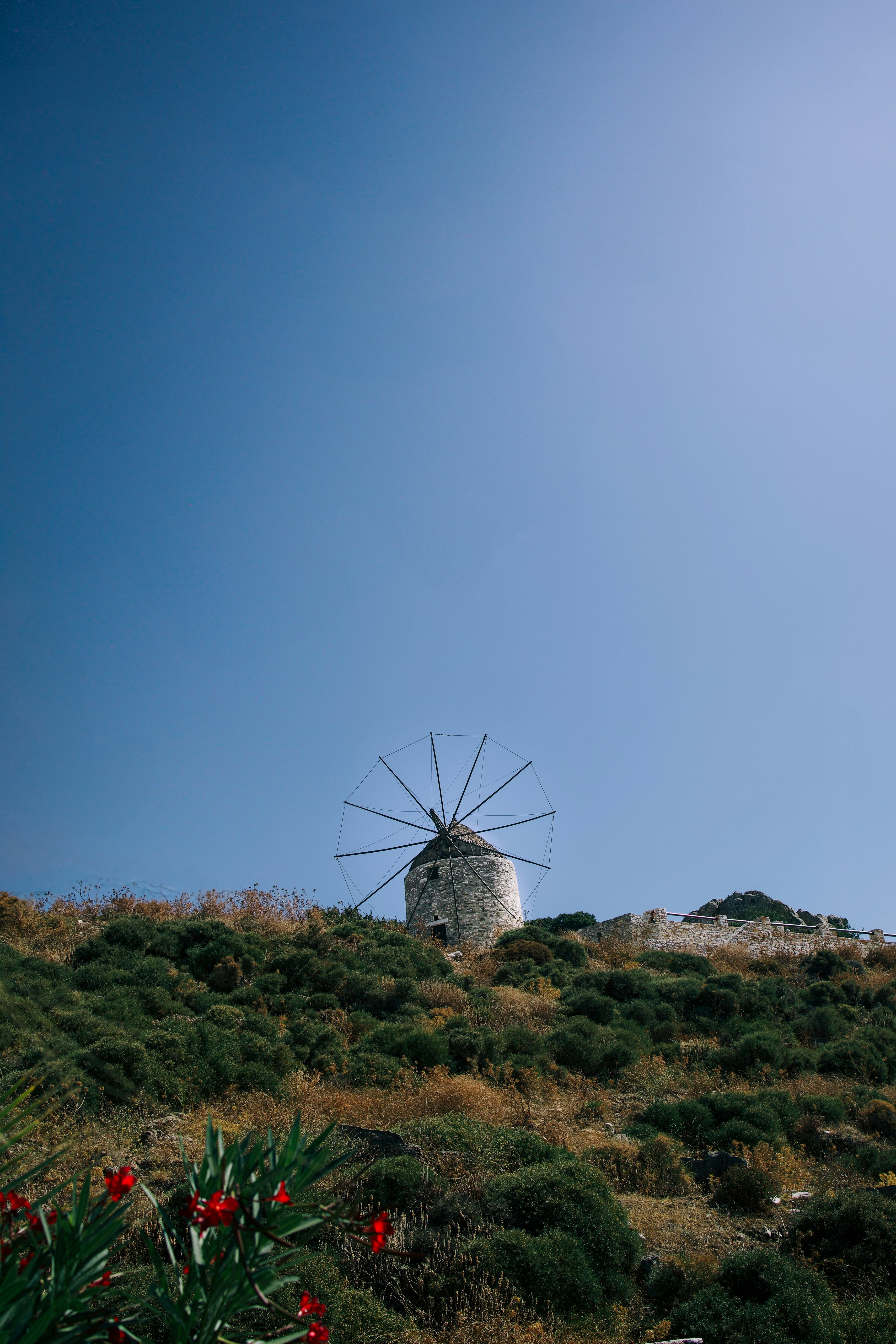Stone windmill overlooking a sunlit hillside beneath a cobalt sky