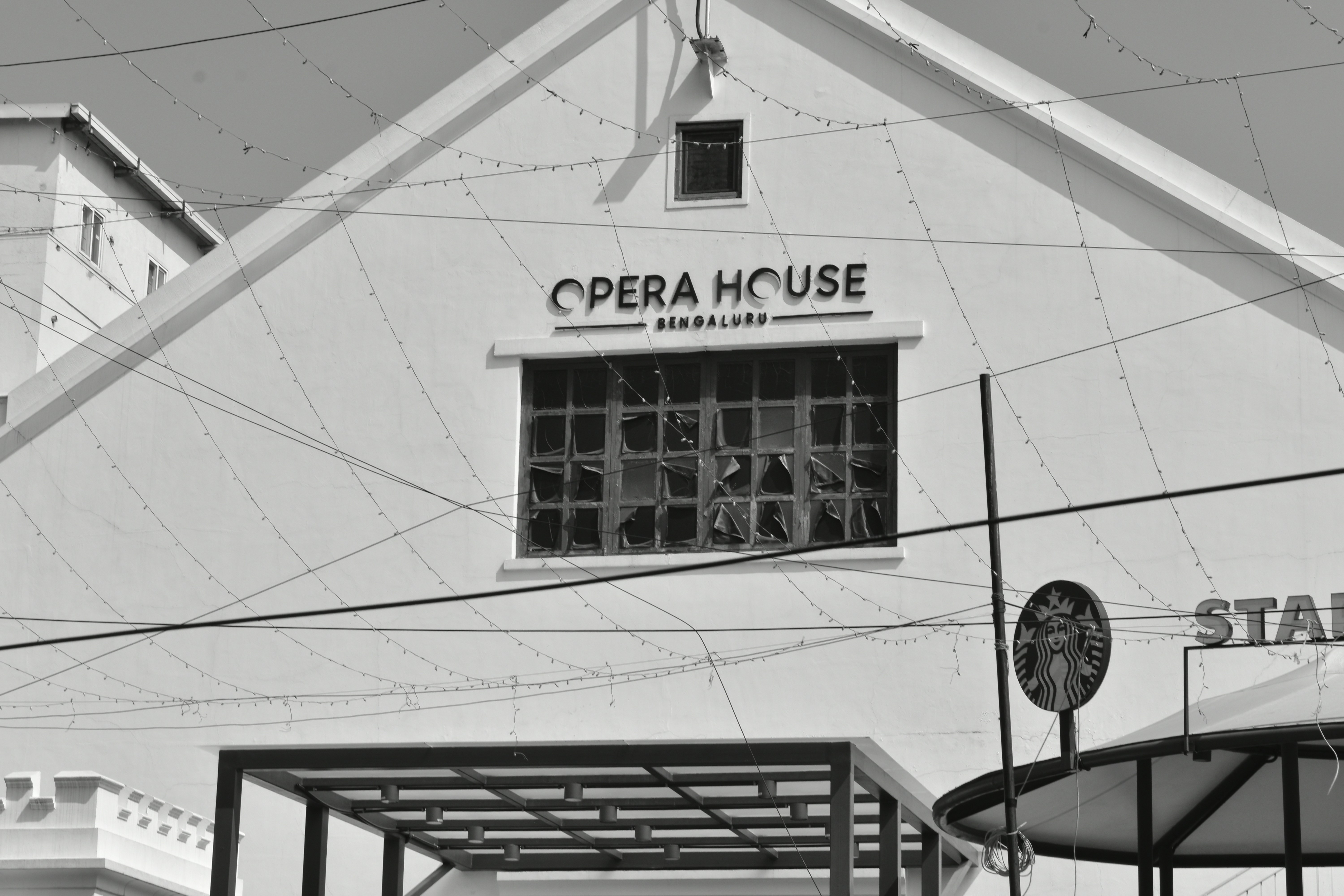 Black and white photo of a building labeled 'Opera House' with architectural details and a visible sign.
