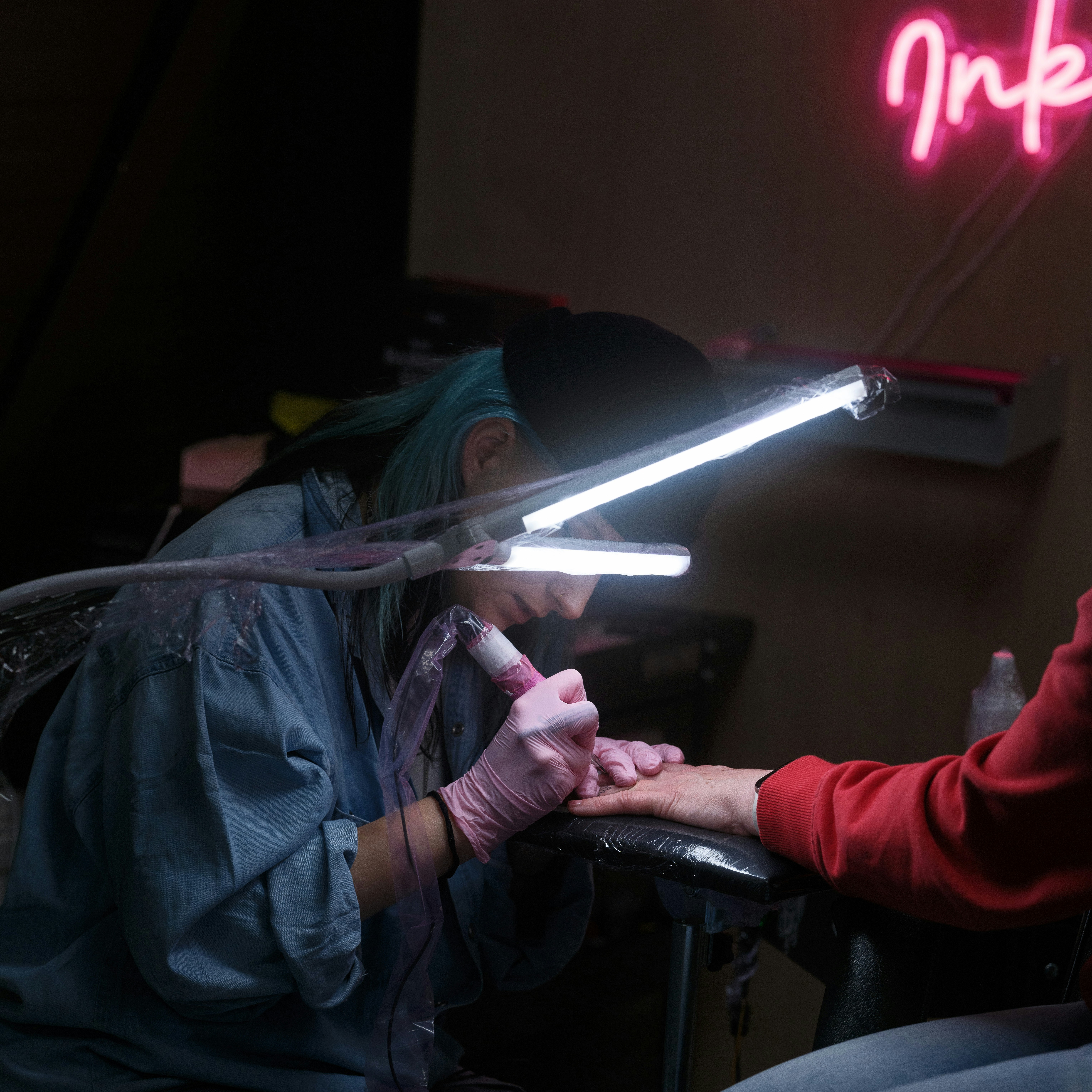 Neon-lit Tattoo Studio: The Lineless Detail of a Hand and Neon Glow