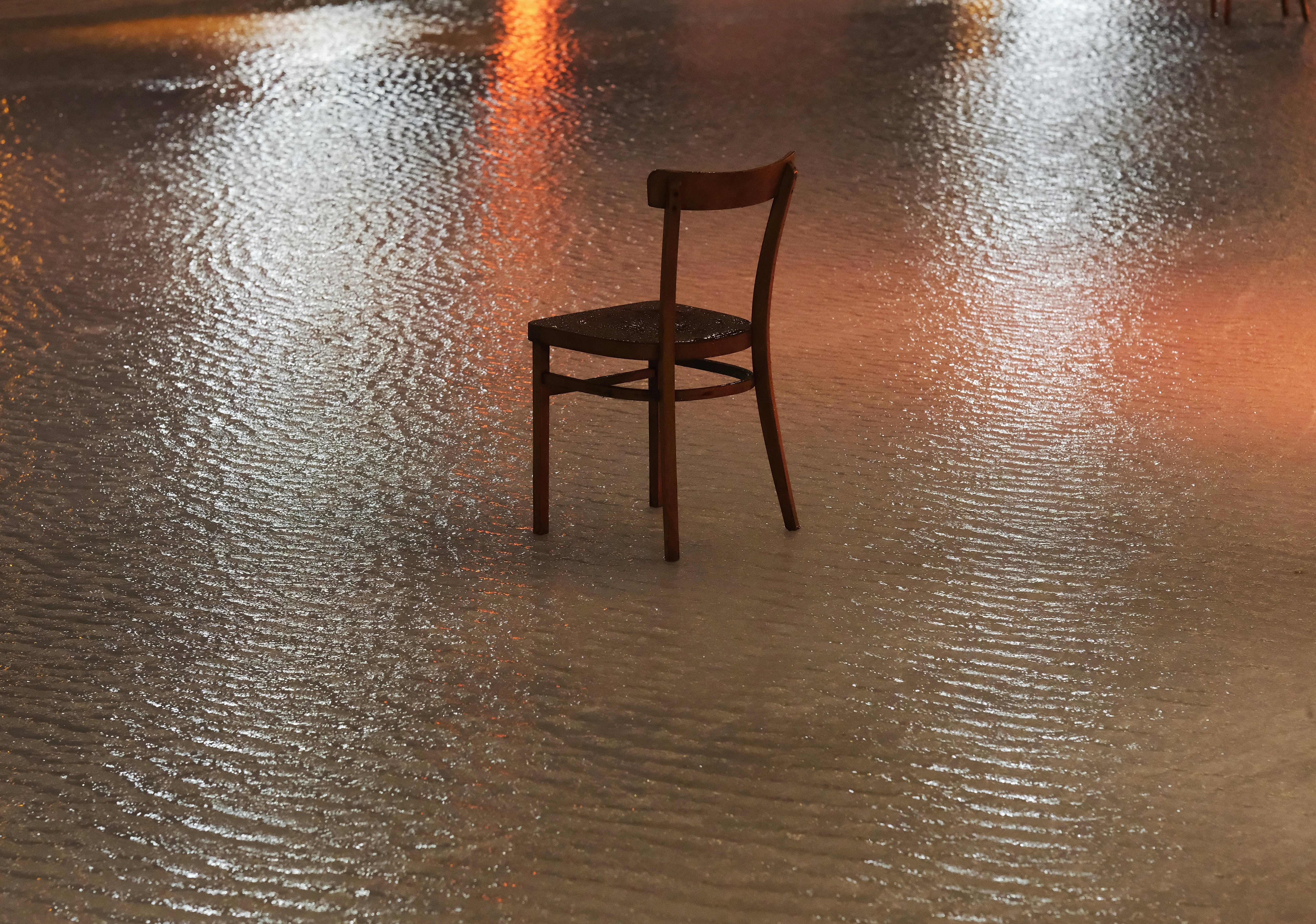 Neon Echoes on Water: A Lone Chair in a Flooded Street