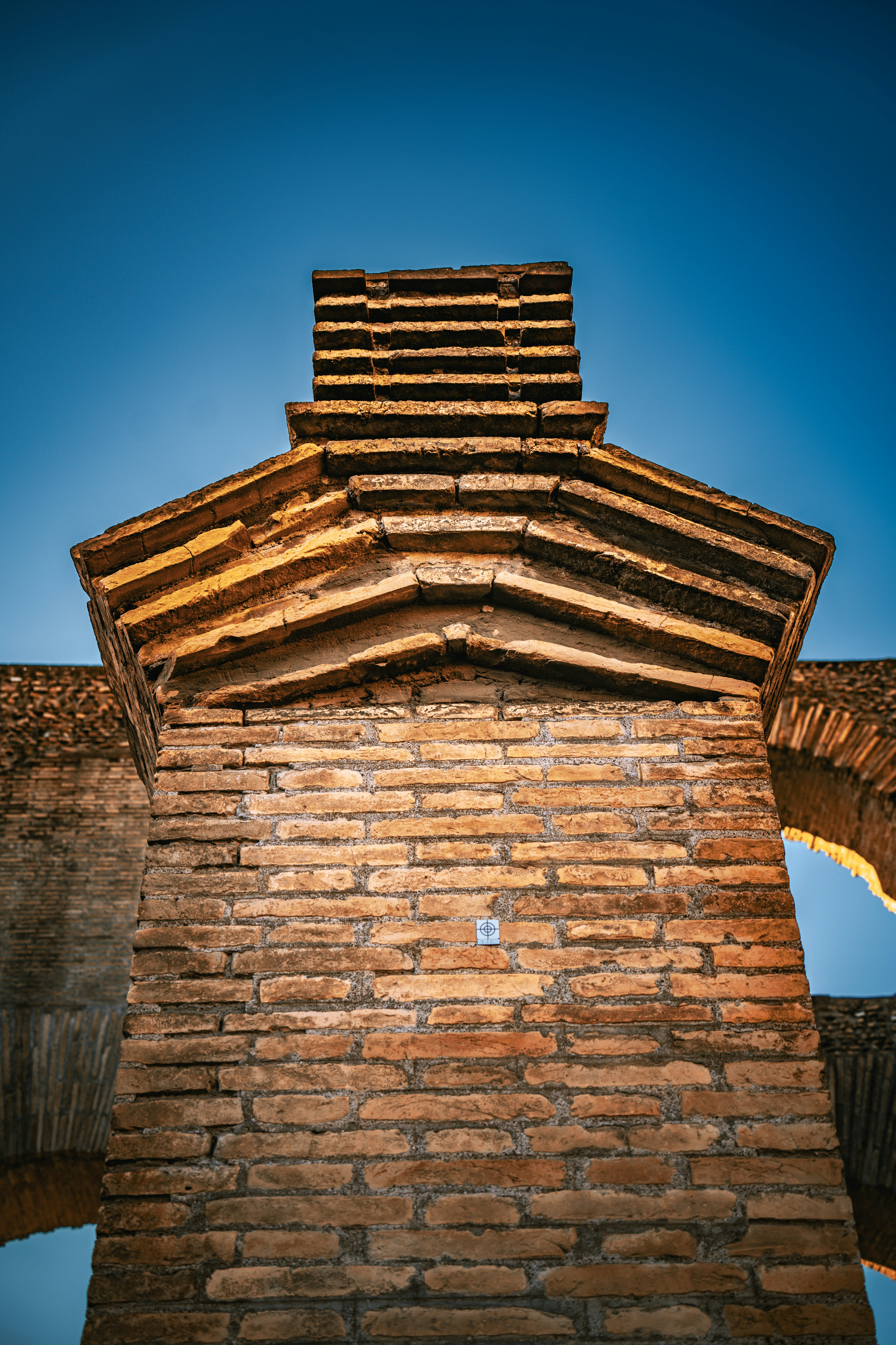 Apex of Brickwork: A Sunlit Chimney Pierces a Cerulean Sky