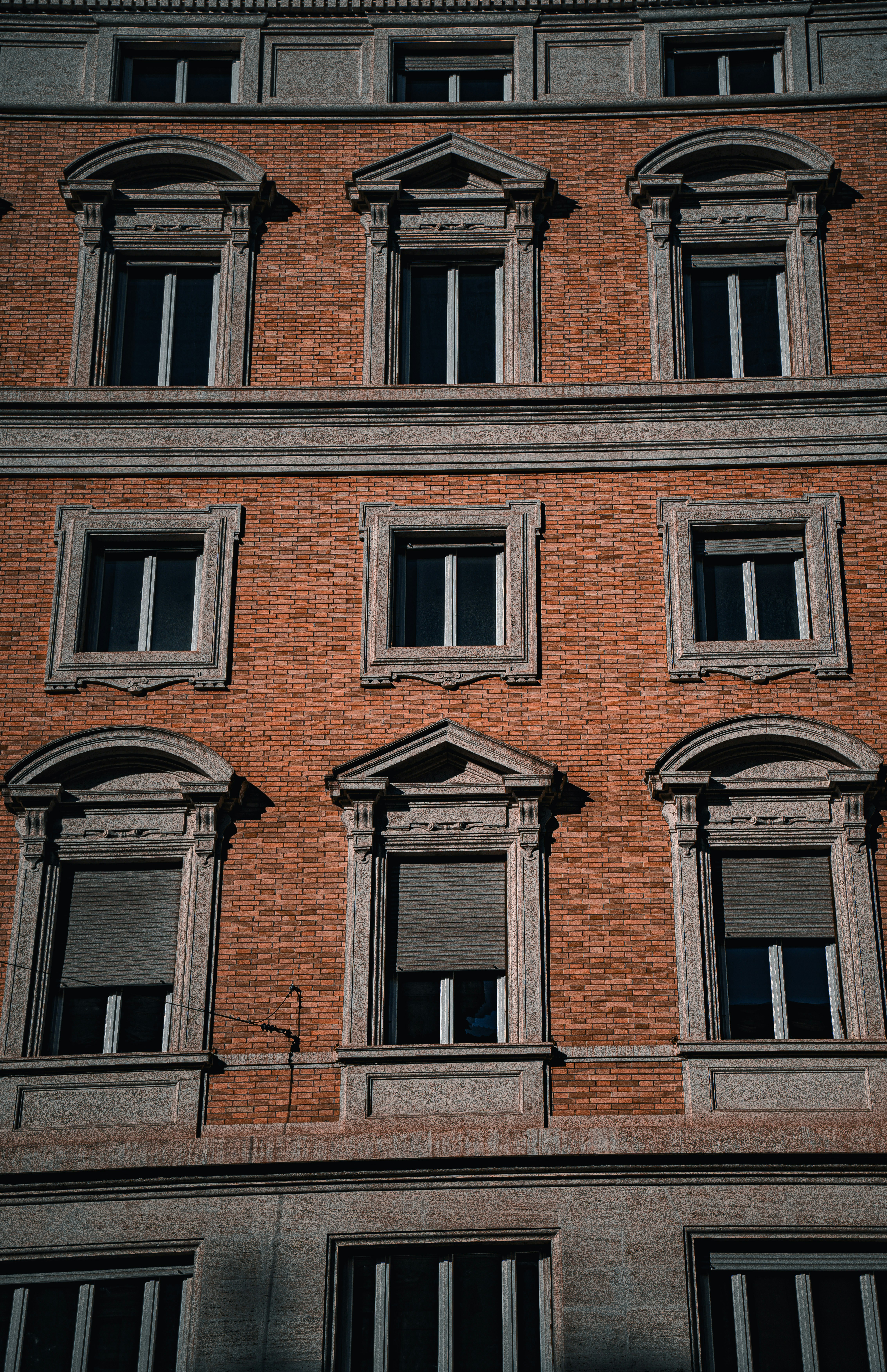 A beautiful red brick building with grey stone window frames, showcasing a perfect blend of classic architecture and rustic charm. A timeless piece of craftsmanship in the heart of the city.