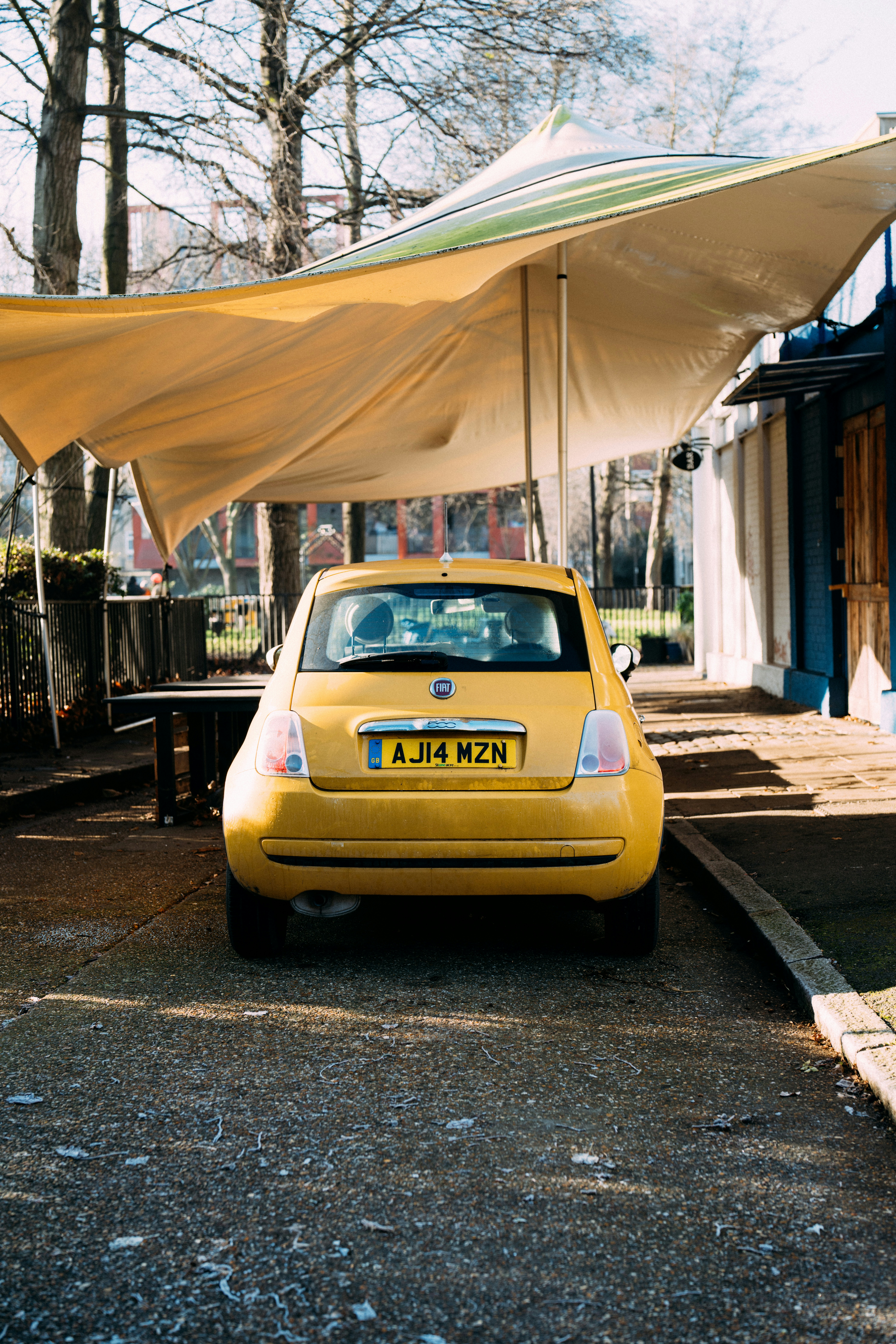 Sunlit Yellow Hatchback Under a Gentle Canopy