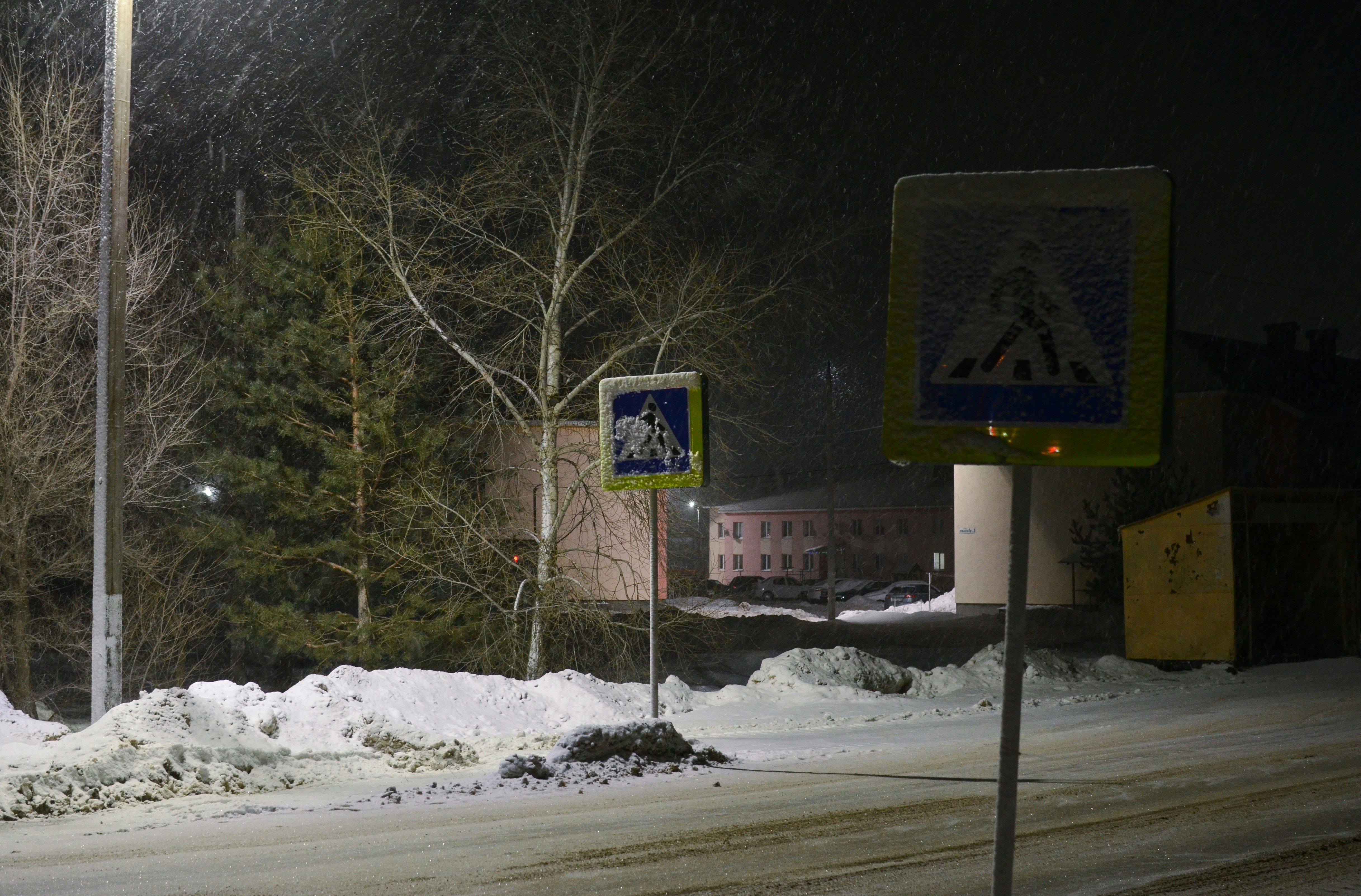 Giant Pedestrian Crossing Sign Guards a Snowbound Street at Night.