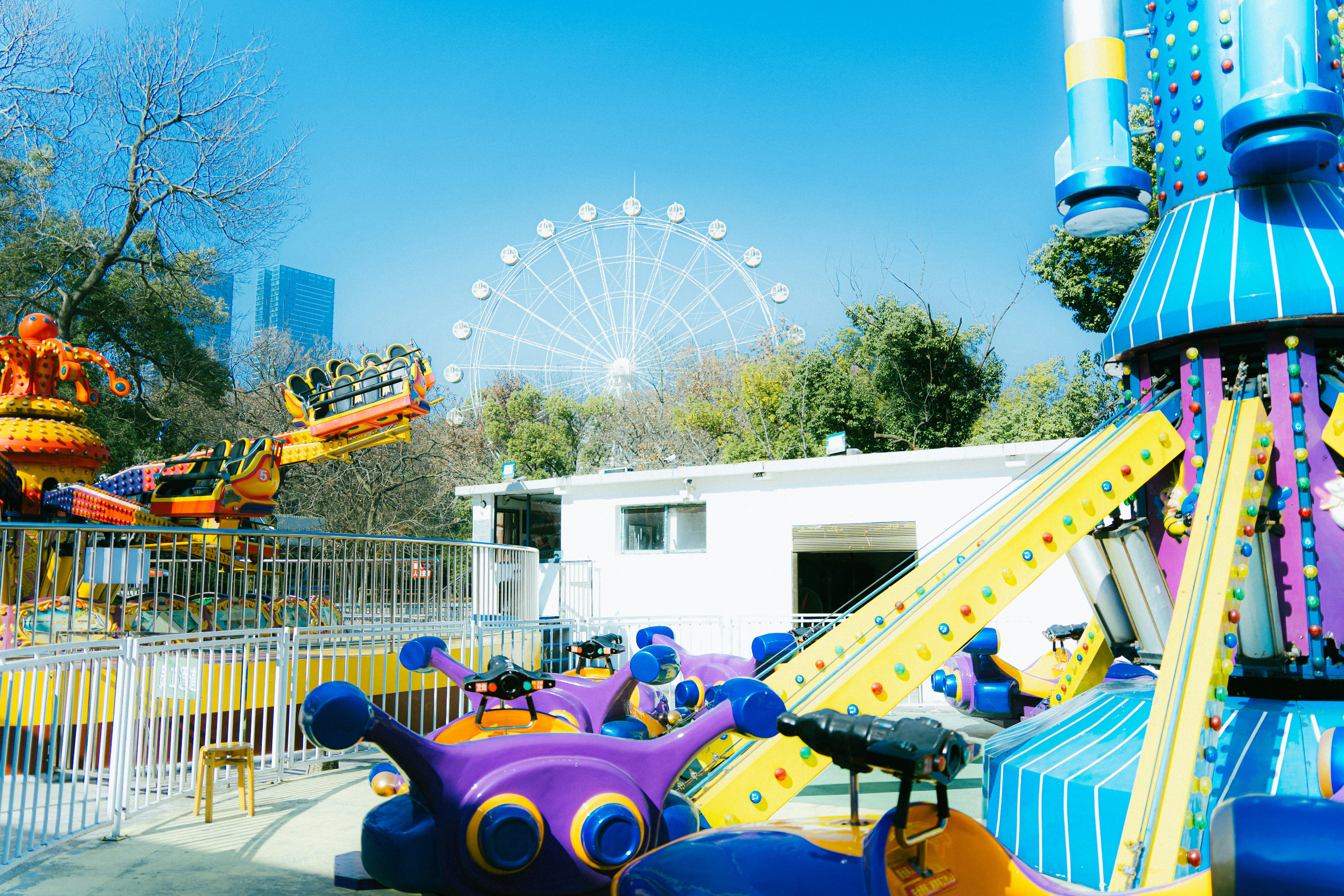 Sunlit Carnival Confluence: Purple Thrill Pod Against a Distant Ferris Wheel