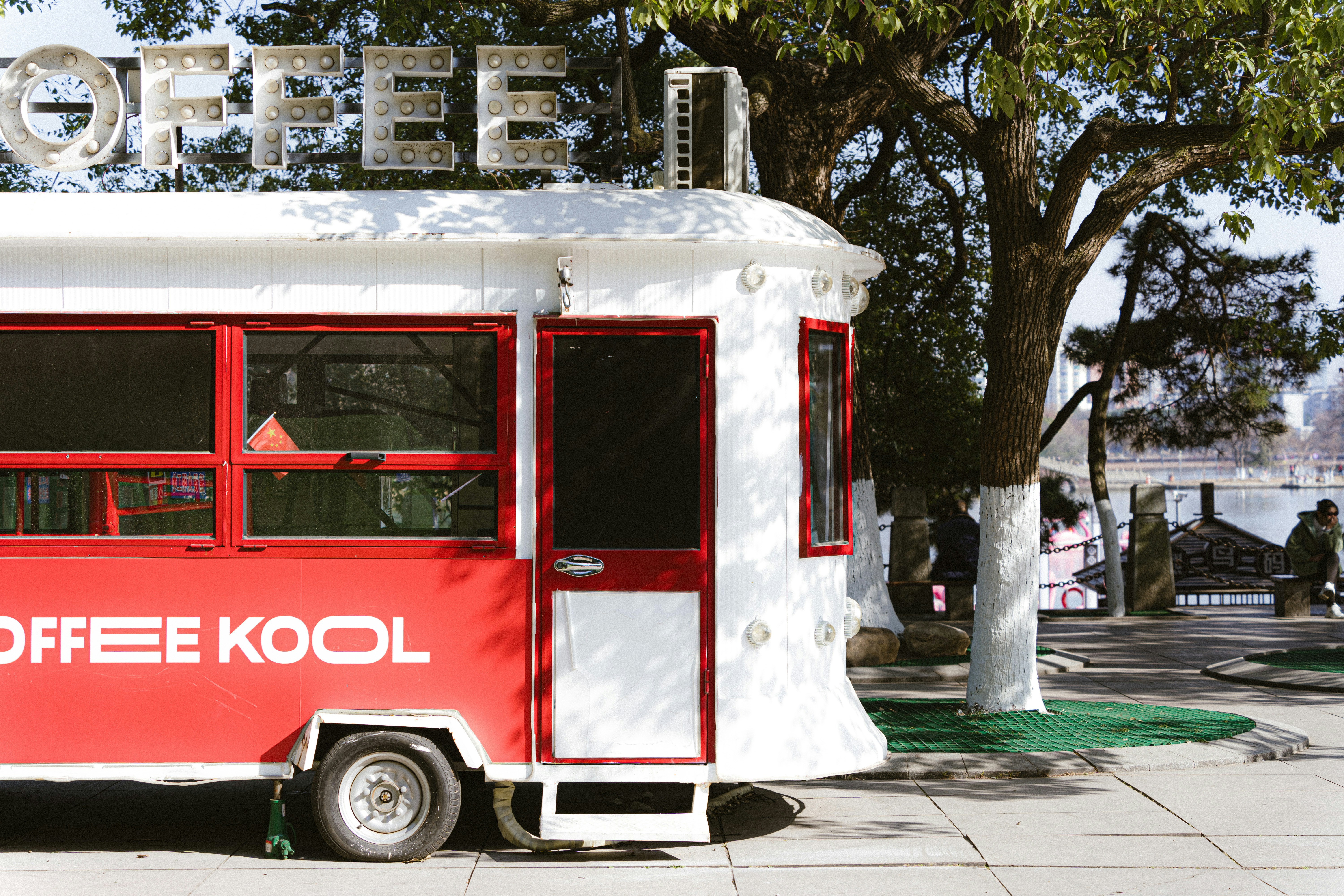 A red and white bus parked next to a tree