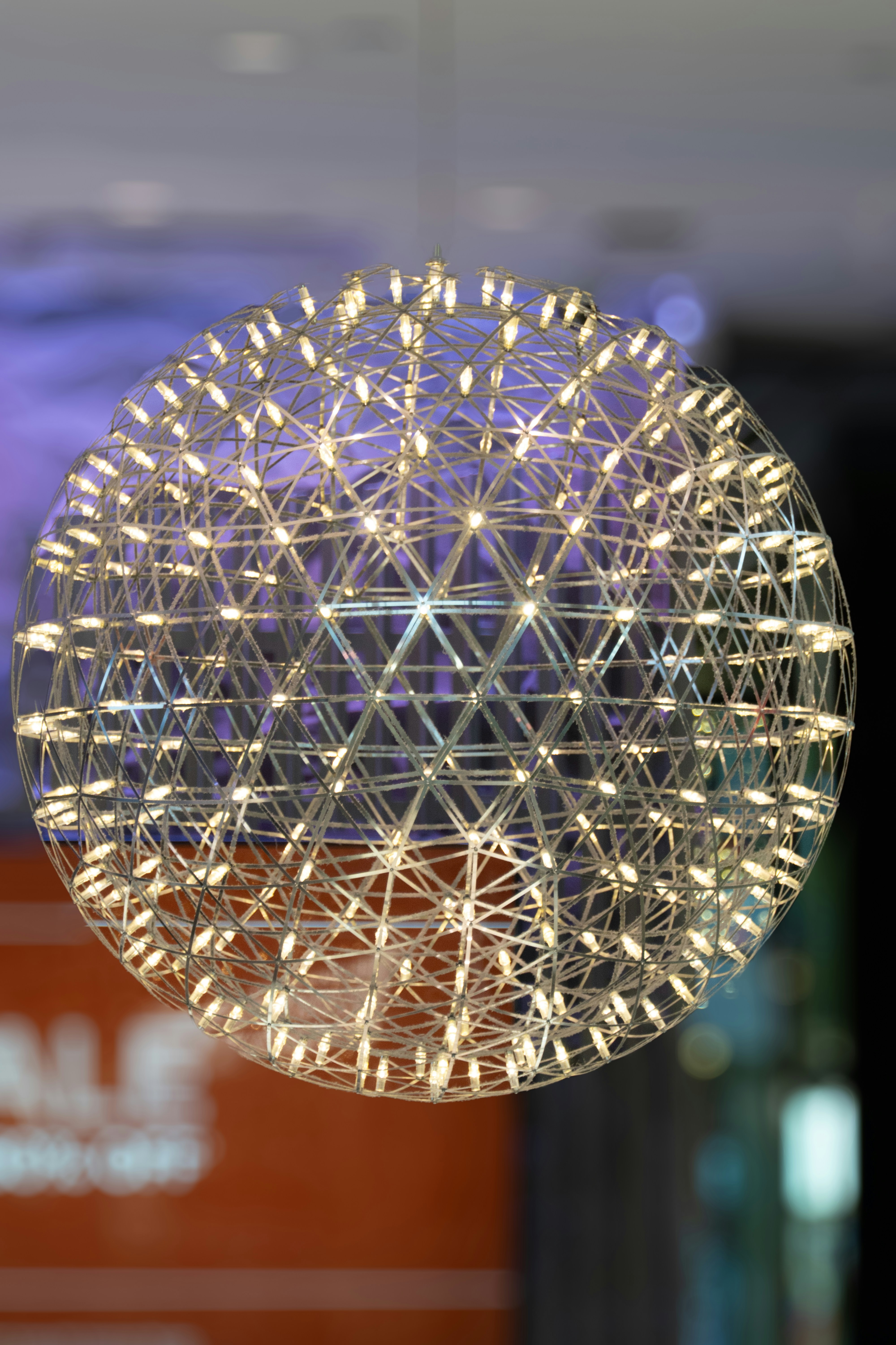Geodesic Sphere of Light: a glowing lattice orb suspended in a softly blurred showroom