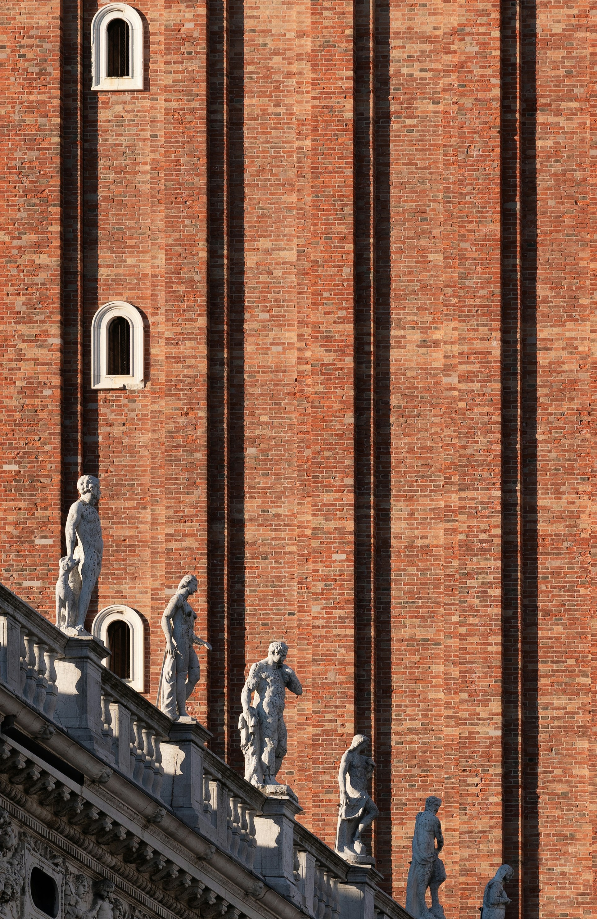 A tall brick building with statues on top of it photo – Free Travel ...