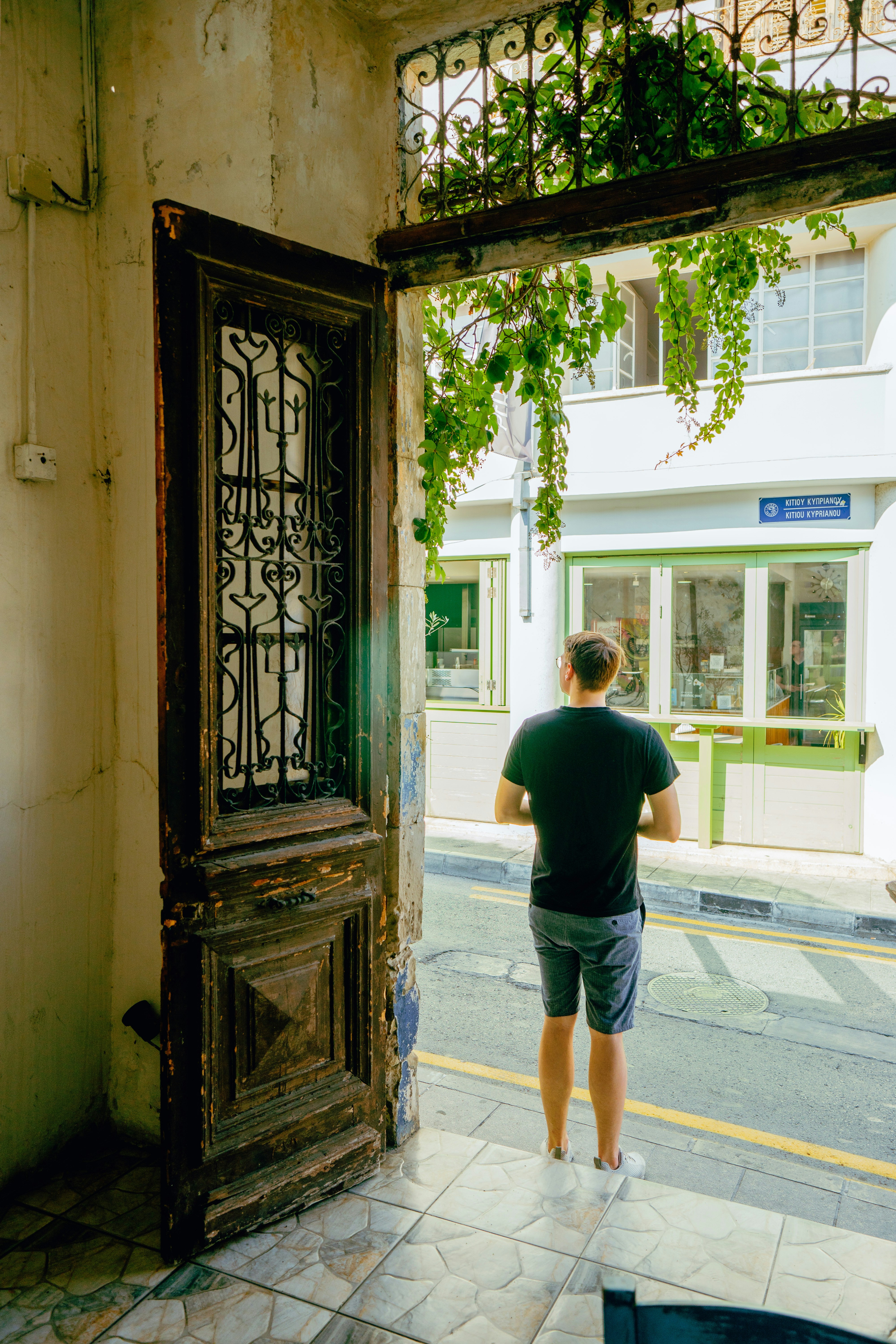 Threshold of Light: A Man Stands in a Weathered Doorway Overlooking a Quiet Street