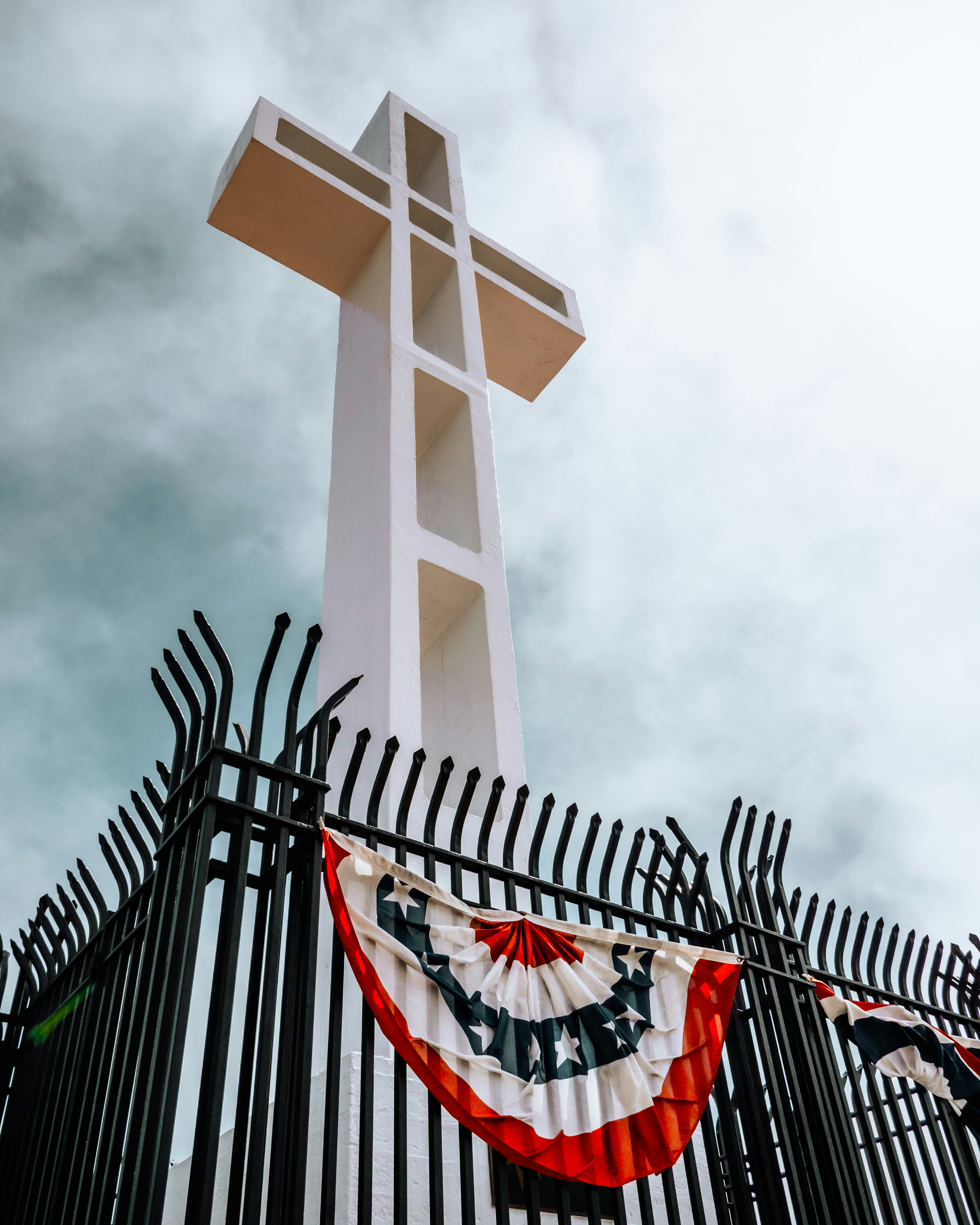 A large white cross on top of a black fence photo – Free Cross Image on ...