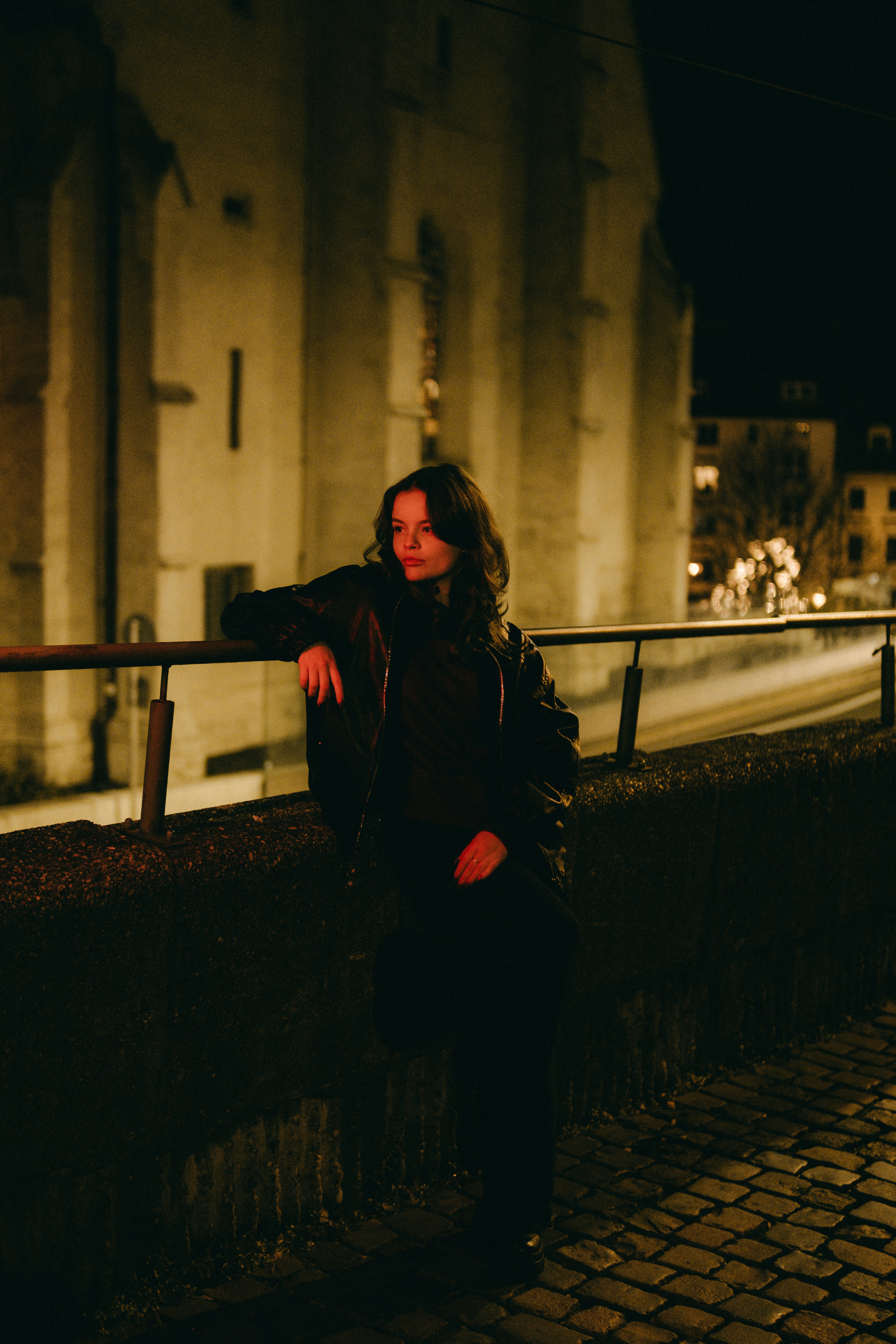 A woman leaning against a railing at night photo – Free City Image on ...
