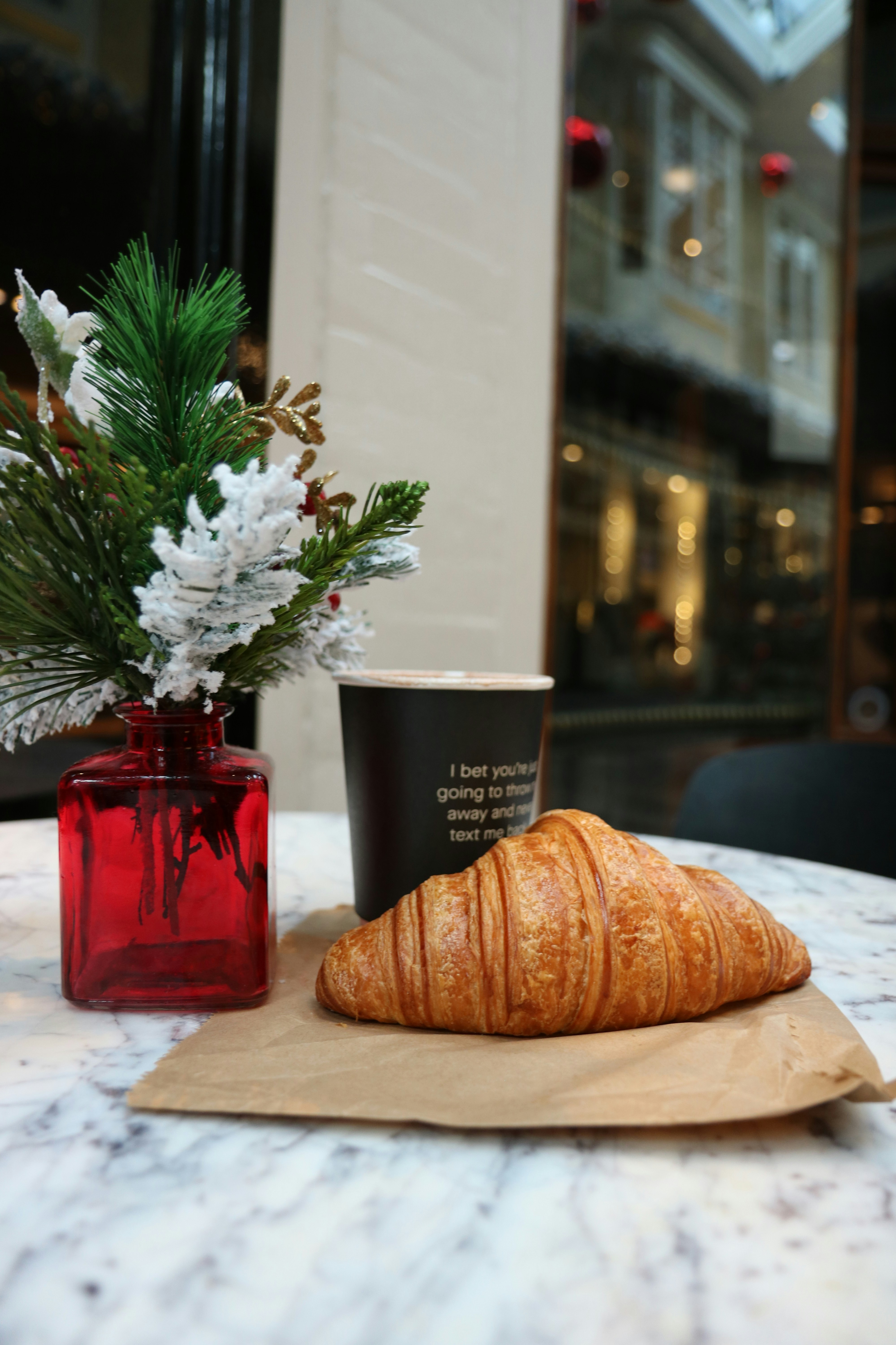 A Croissant Moment: Marble Table, Coffee, and Festive Greens