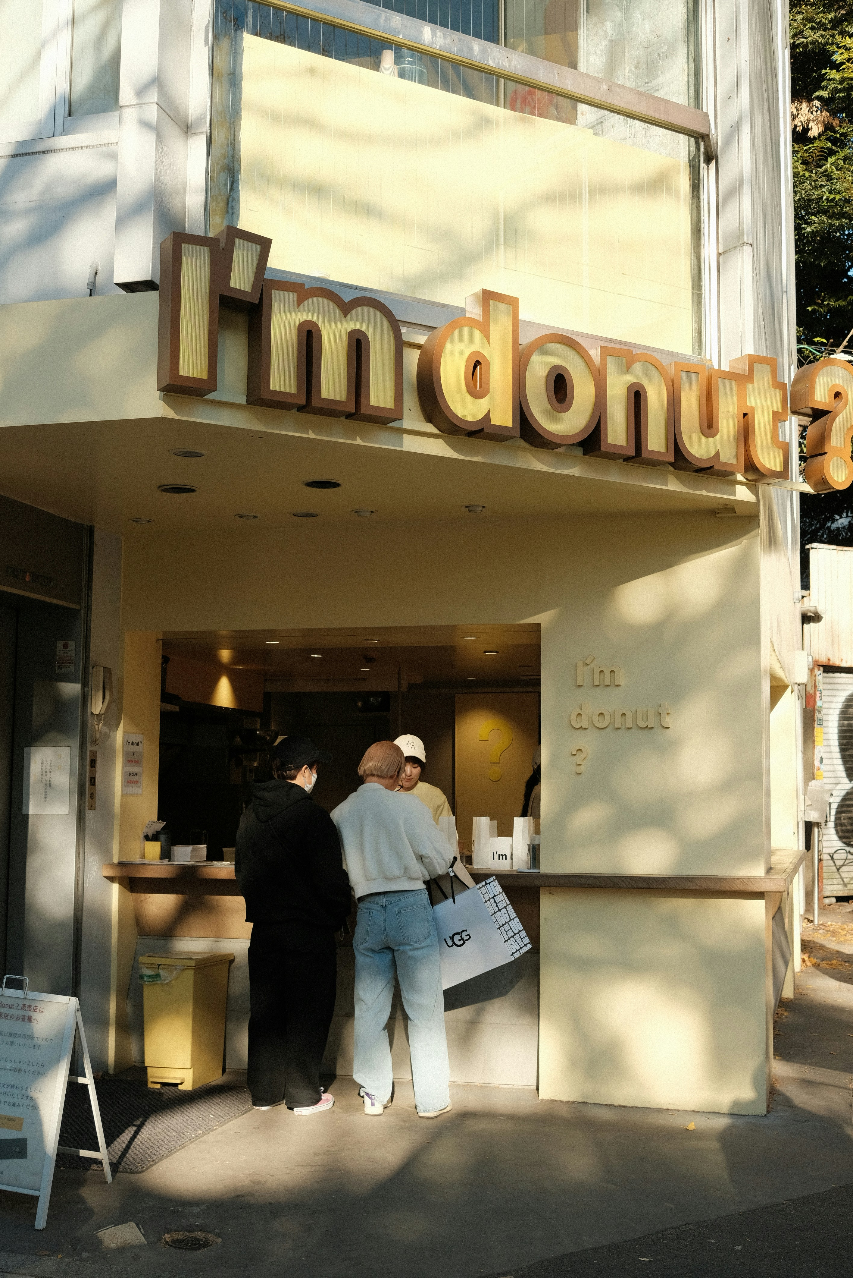 A couple of people standing outside of a donut shop photo – Free I'm ...