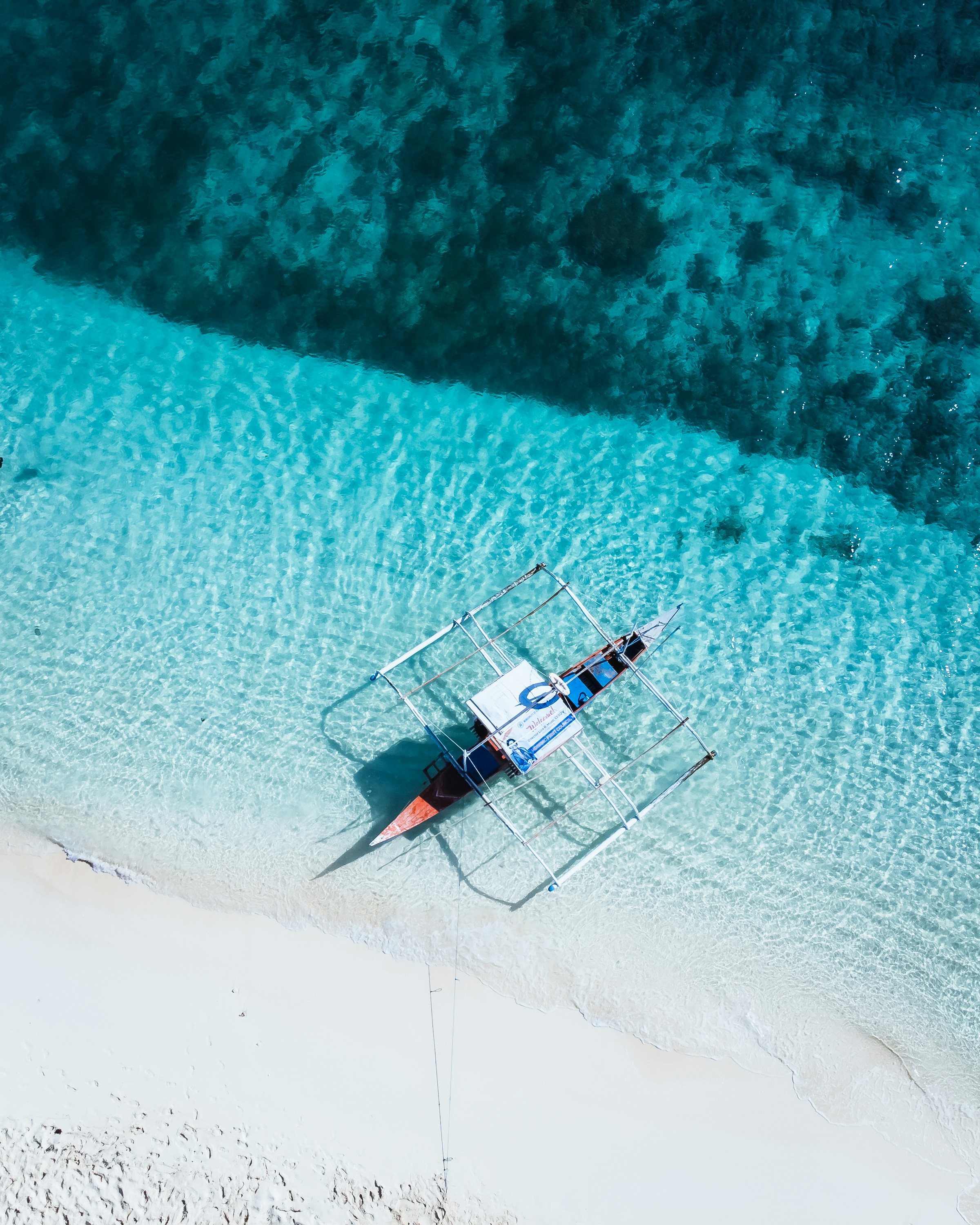 A boat floating on top of a sandy beach next to the ocean photo – Free ...