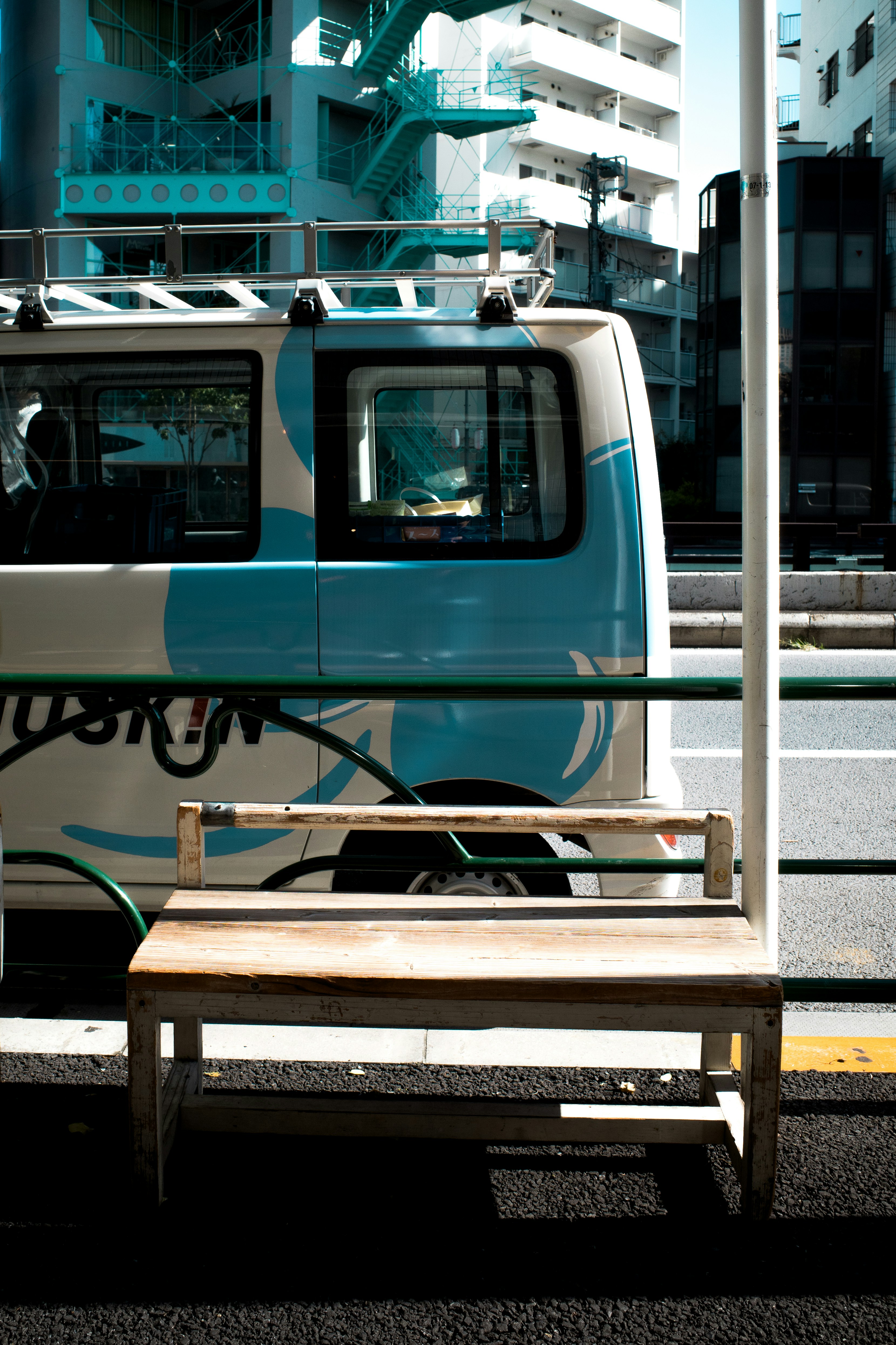 Teal Transit, Wooden Pause: A Street-Side Scene
