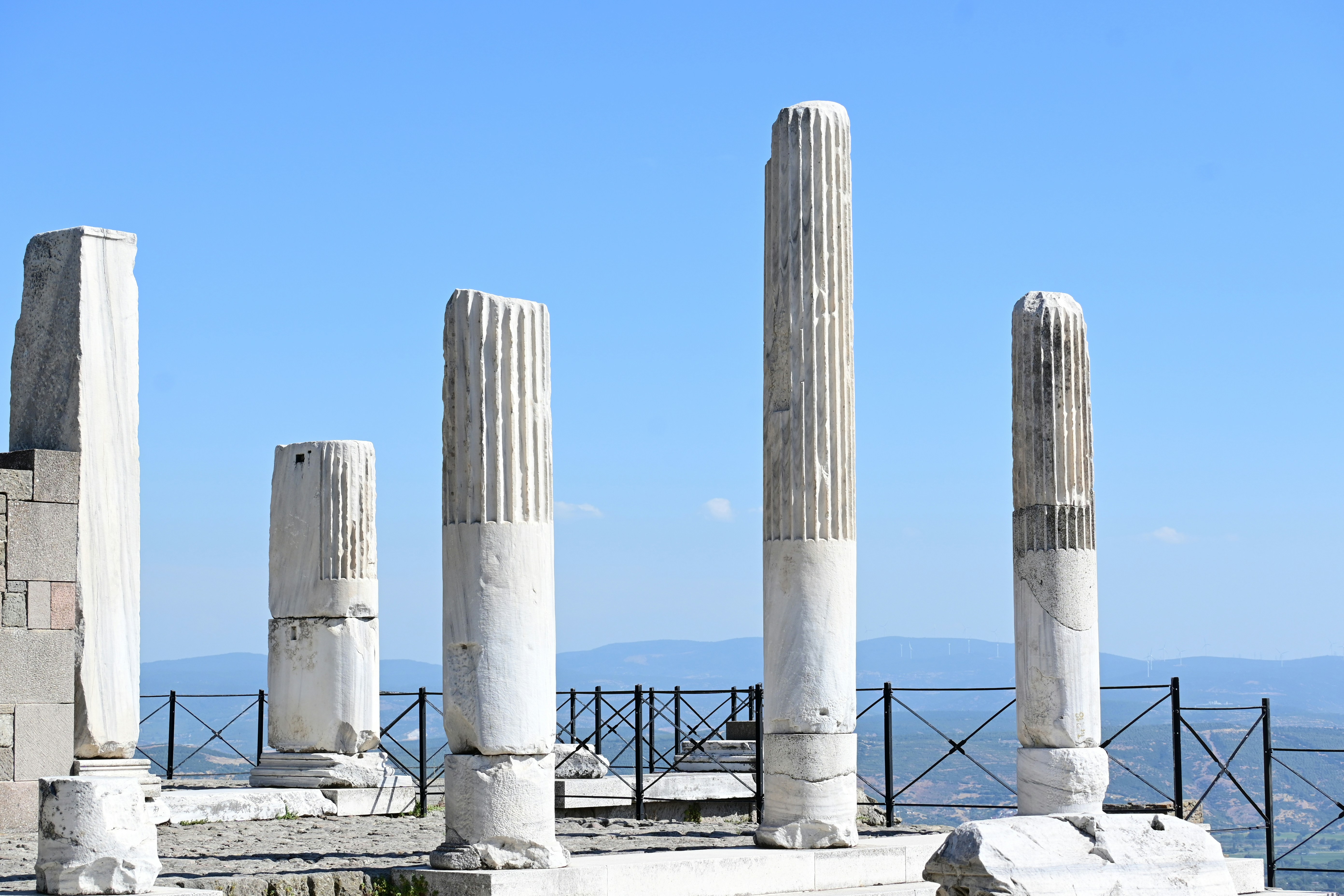 Stone Sentinels Over the Aegean: Cliffside Ruins in Bright Sky