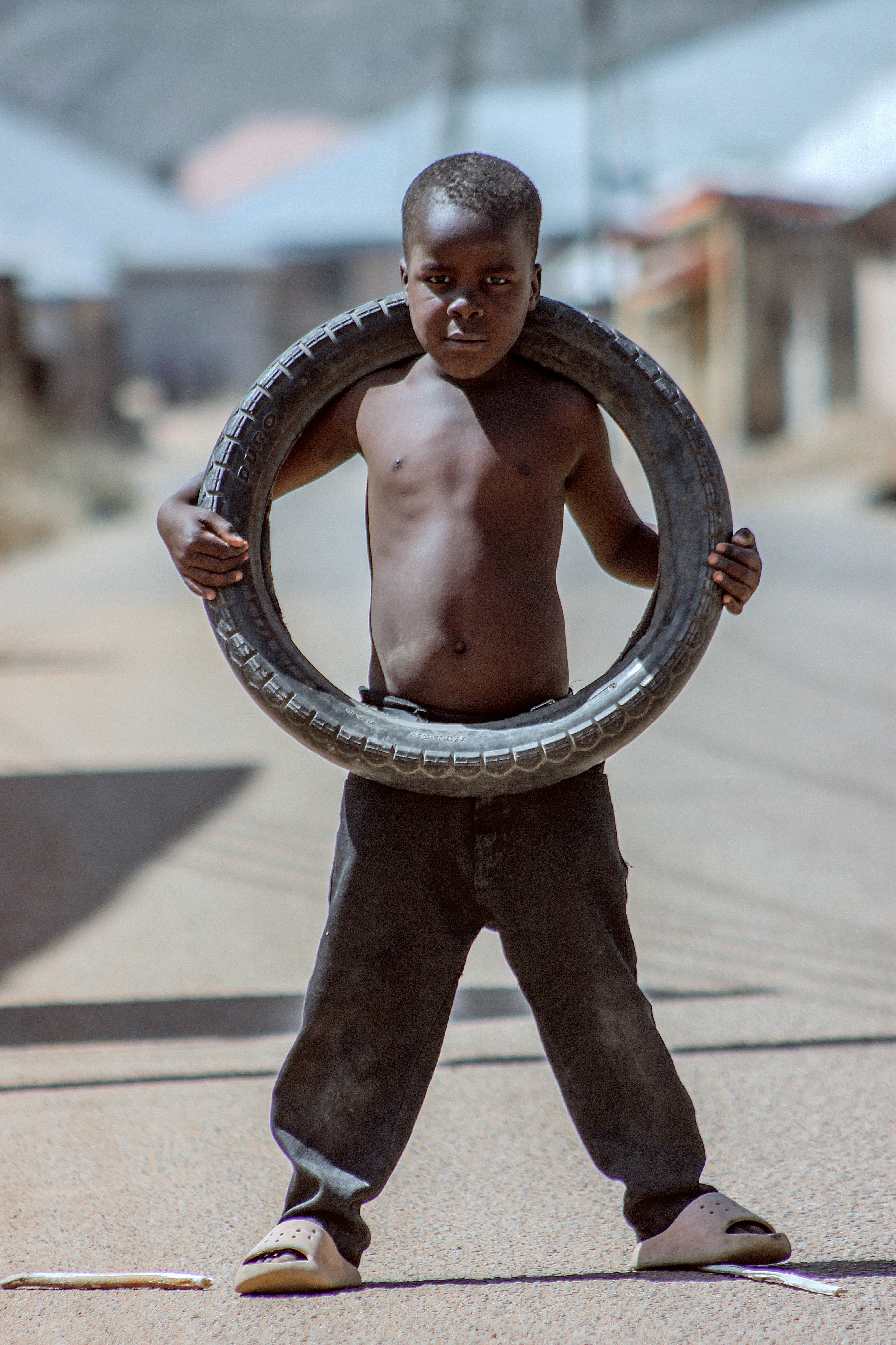 Through the Tire: A Portrait of Determination on a Dusty Street