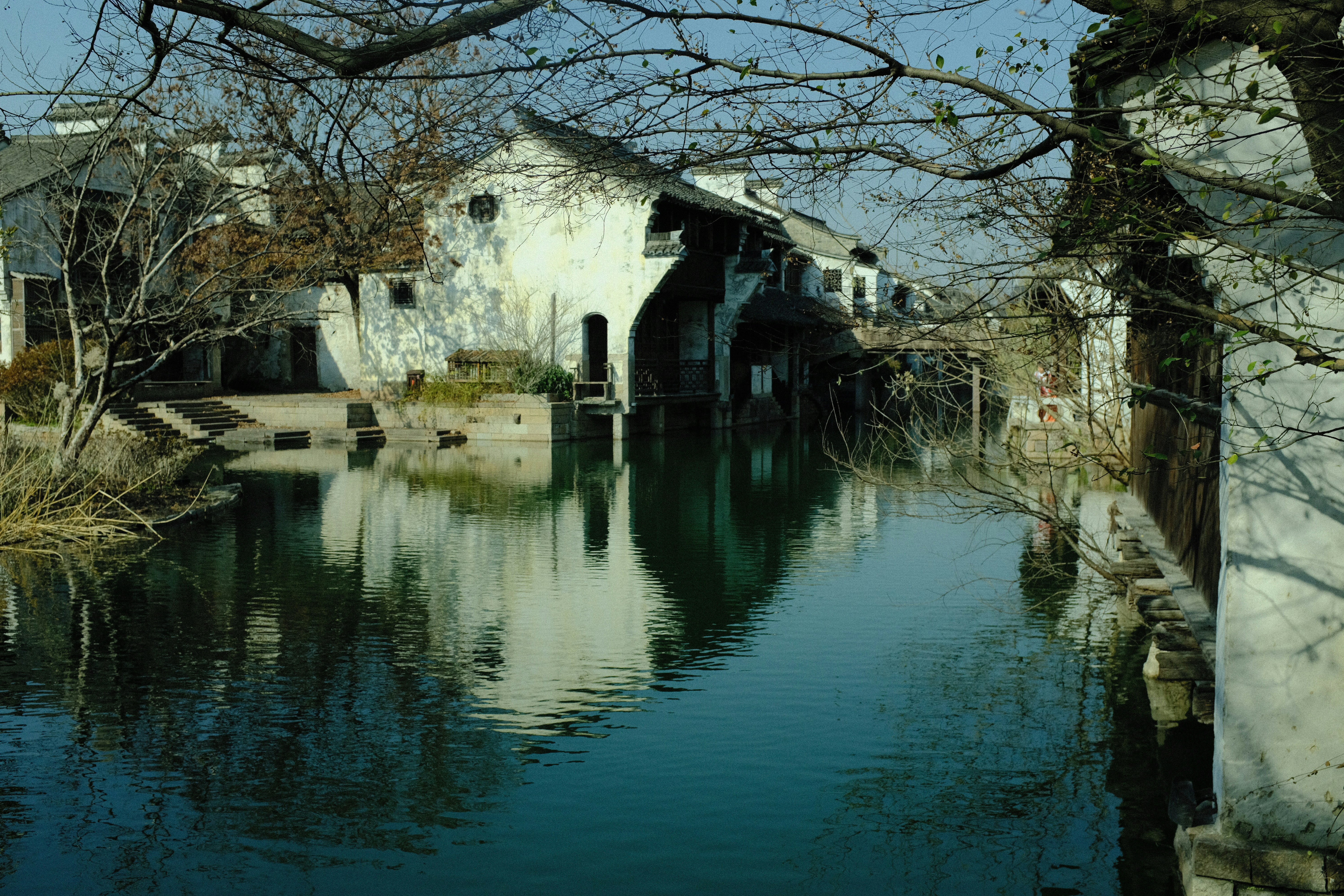 Serene canal reflecting traditional whitewashed buildings under a clear blue sky.