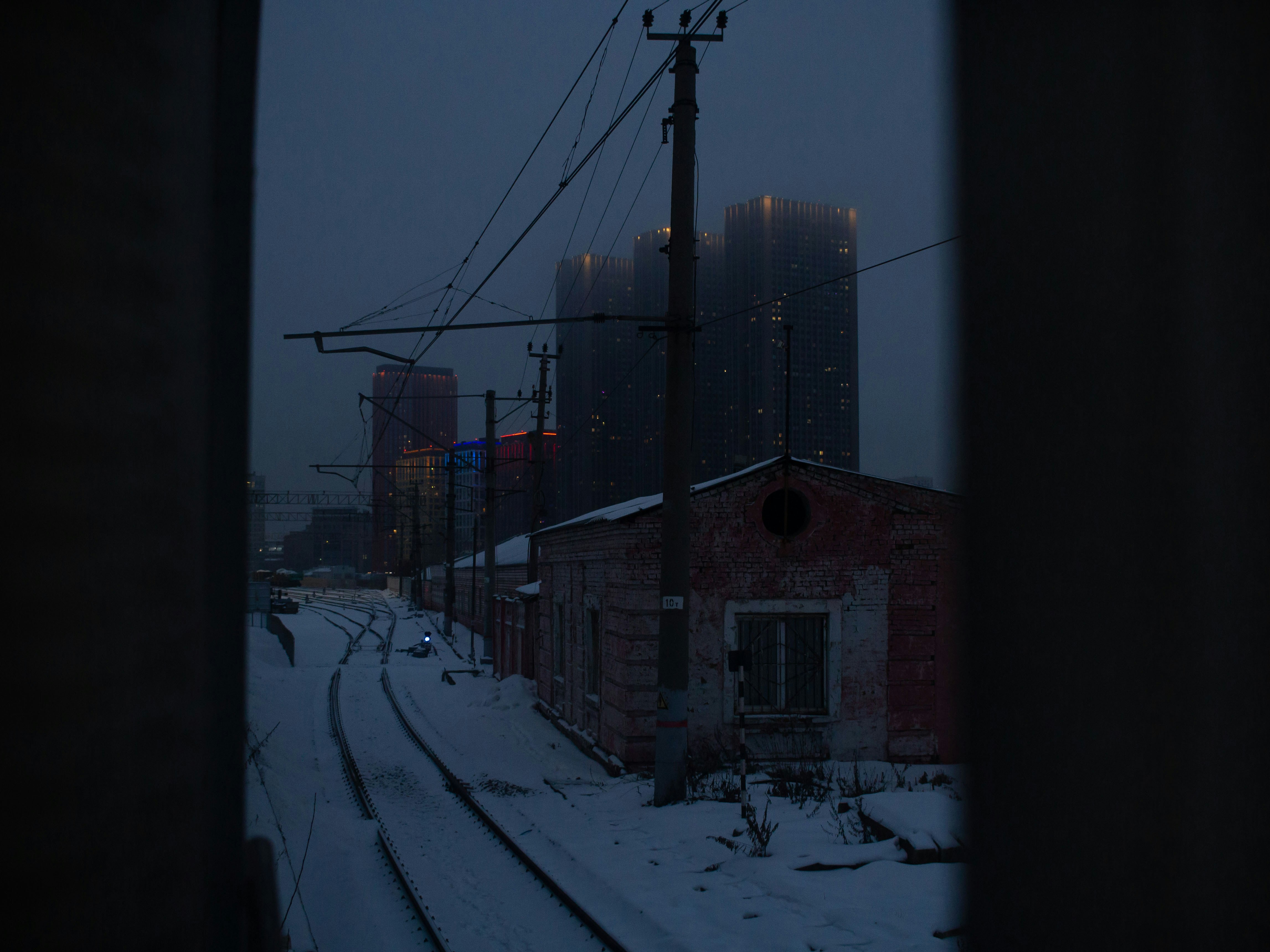 Blue Hour Corridor: Snow Rails Toward a Distant Skyscraper
