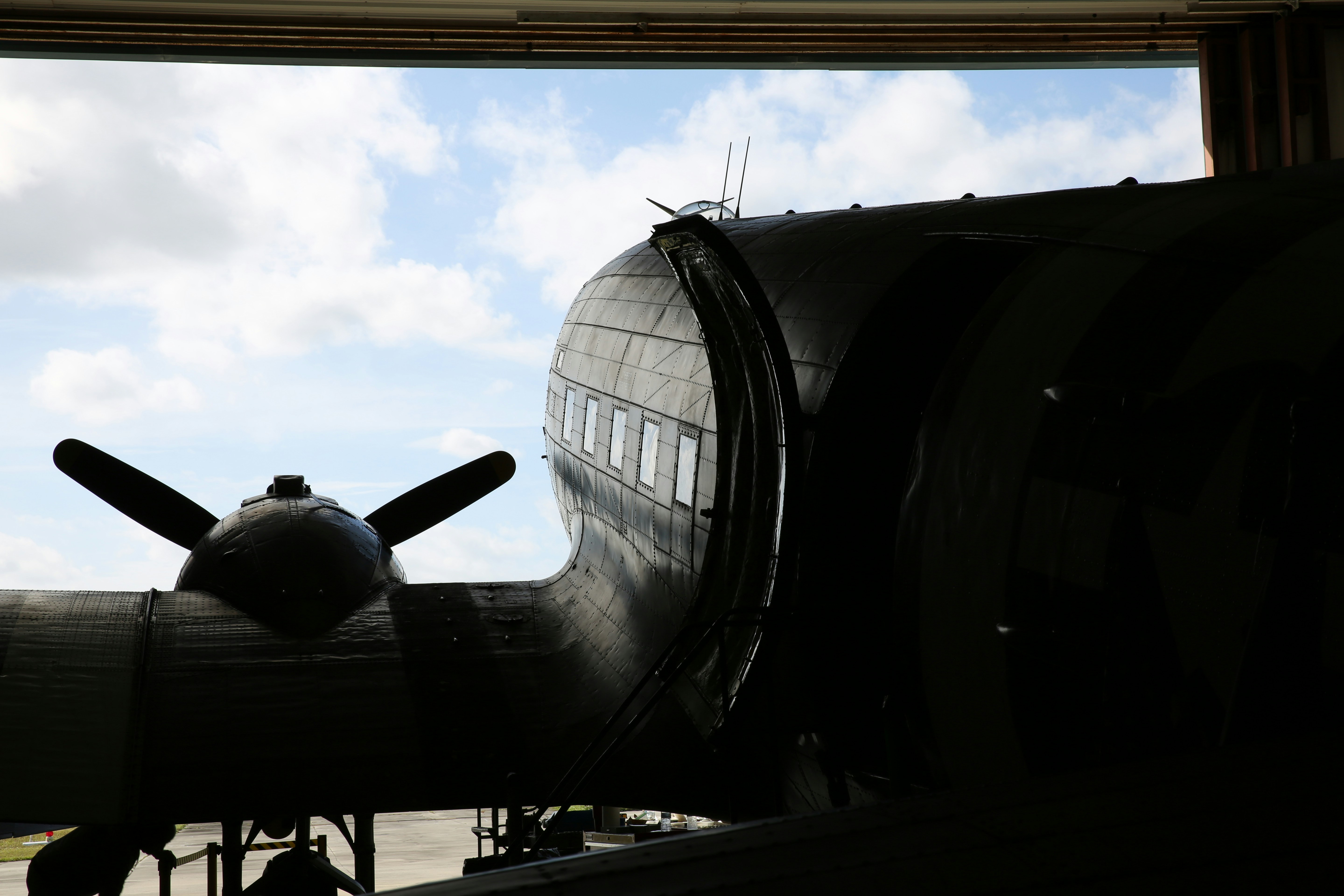 Silhouette of a vintage aircraft against a bright sky, highlighting its iconic design and propeller details.