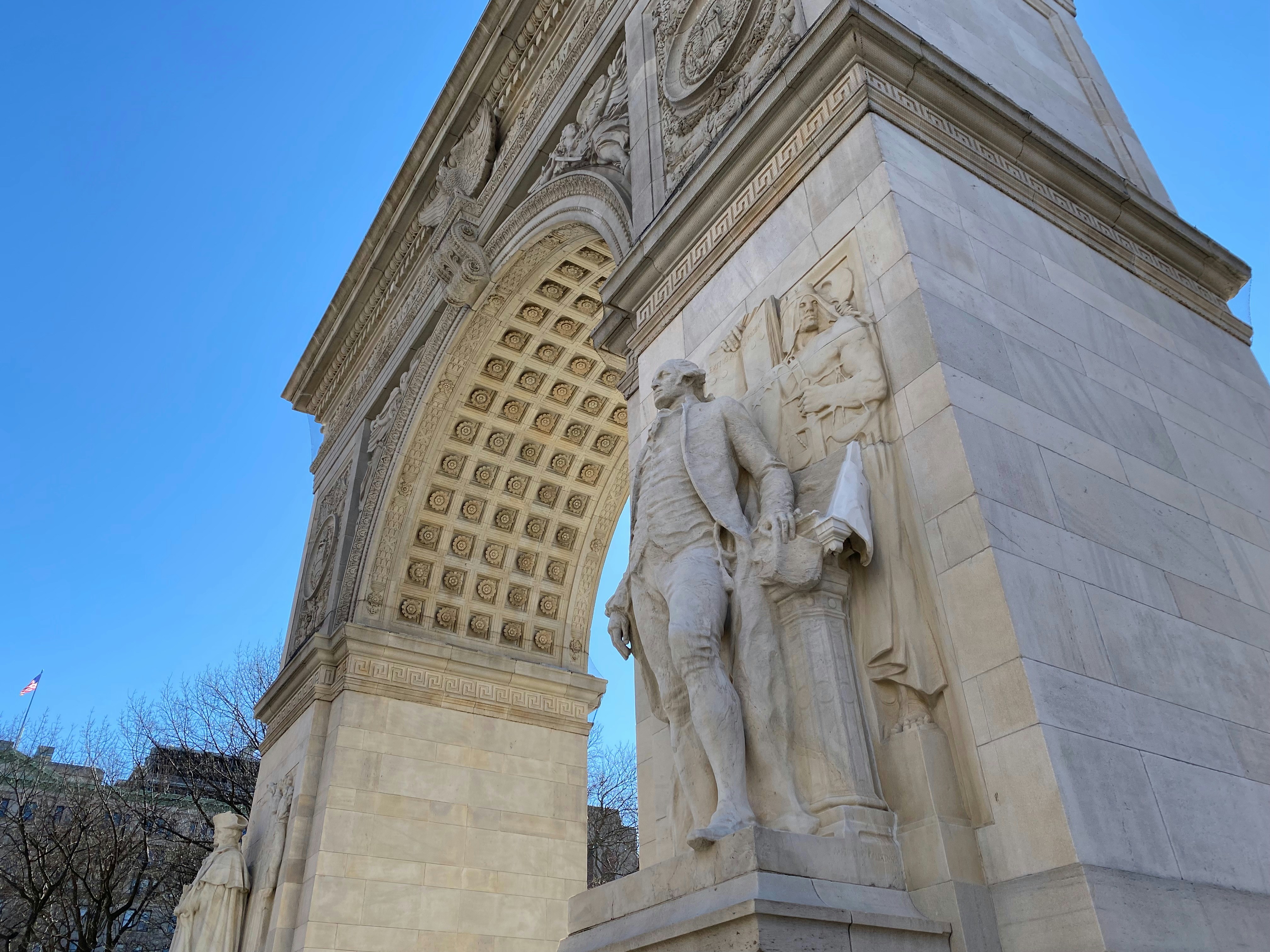 Stone Sentinel: Sculpted Figures Guard the Arch Under a Cerulean Sky