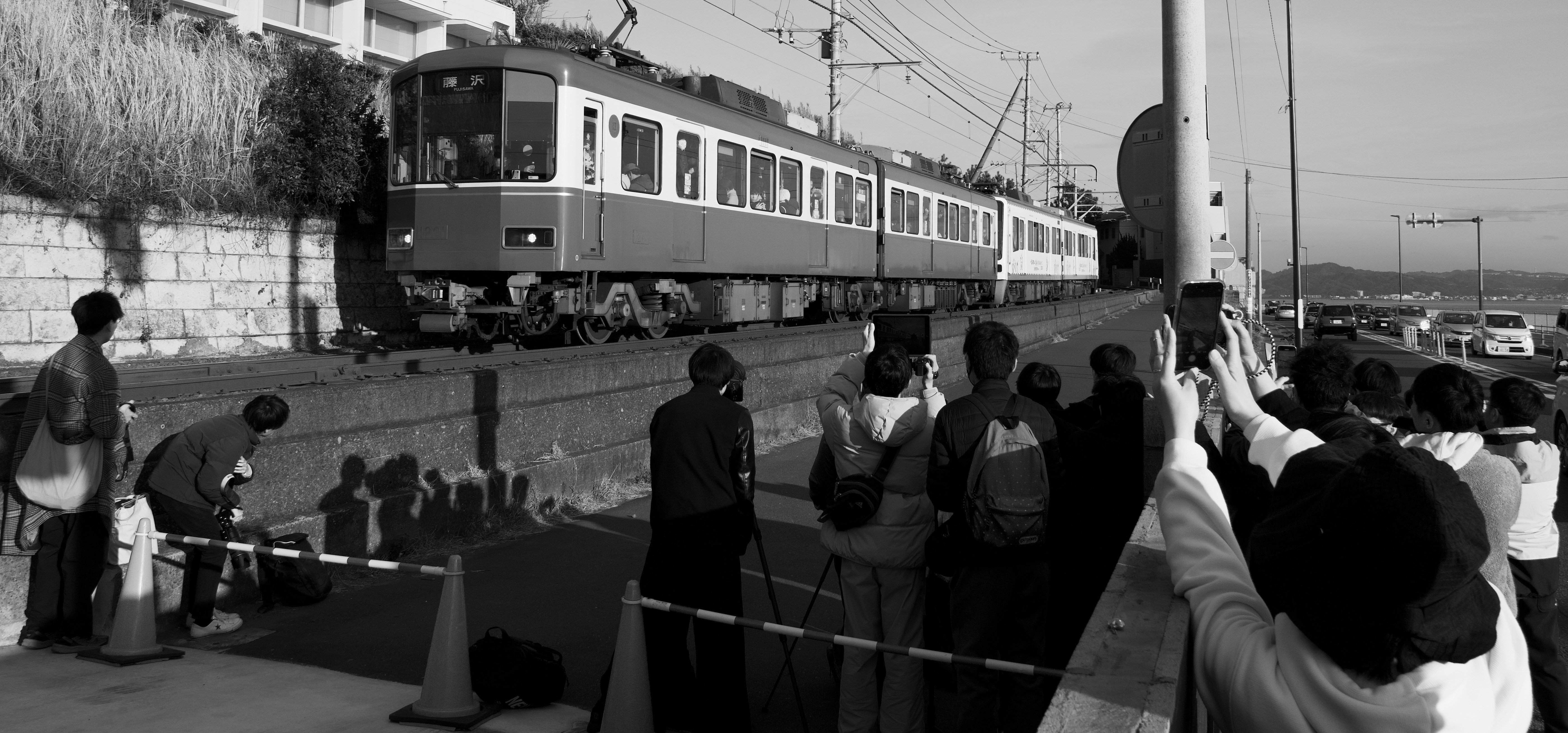 Group of people waving at a departing train from a platform under a clear sky.