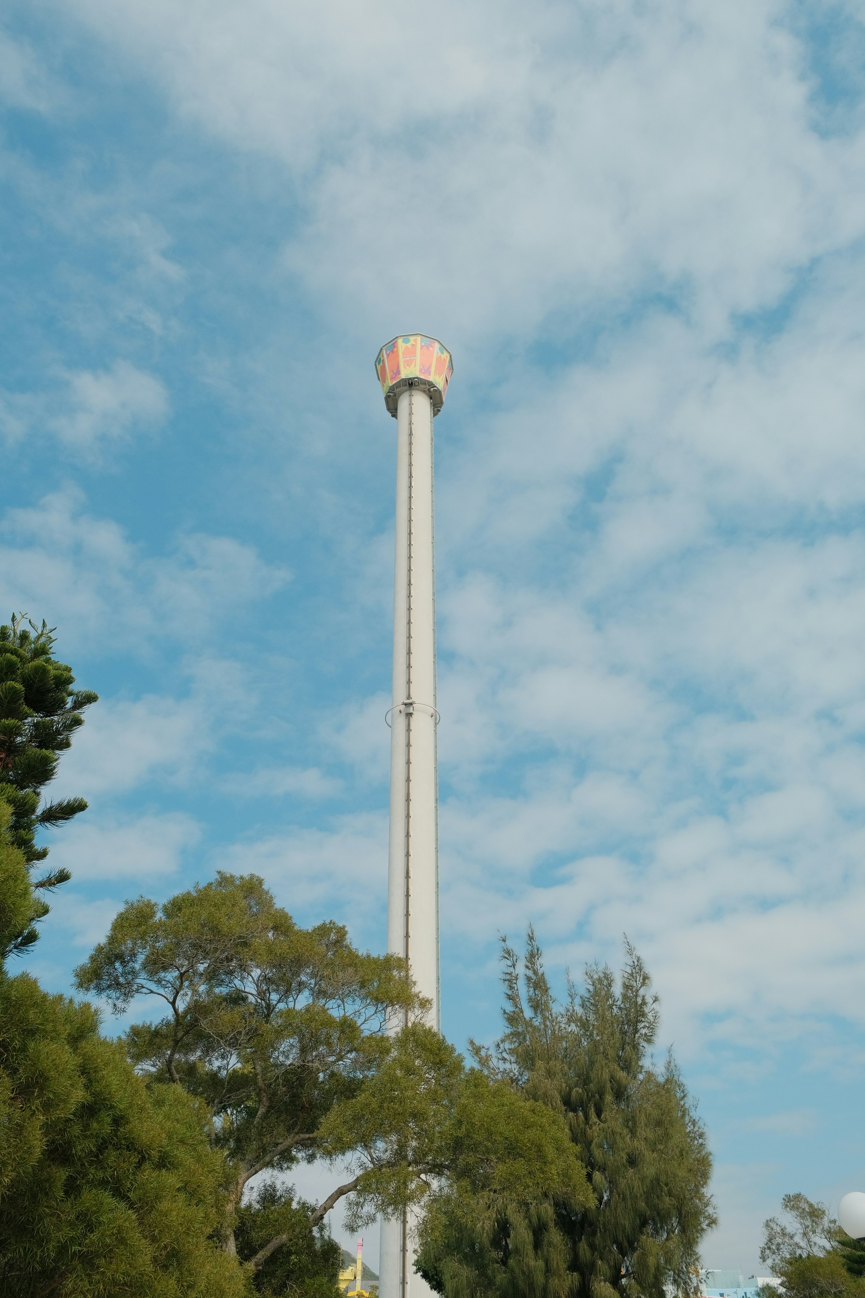 Pastel Crown Above the Pines: A slender observation tower pierces a bright blue sky