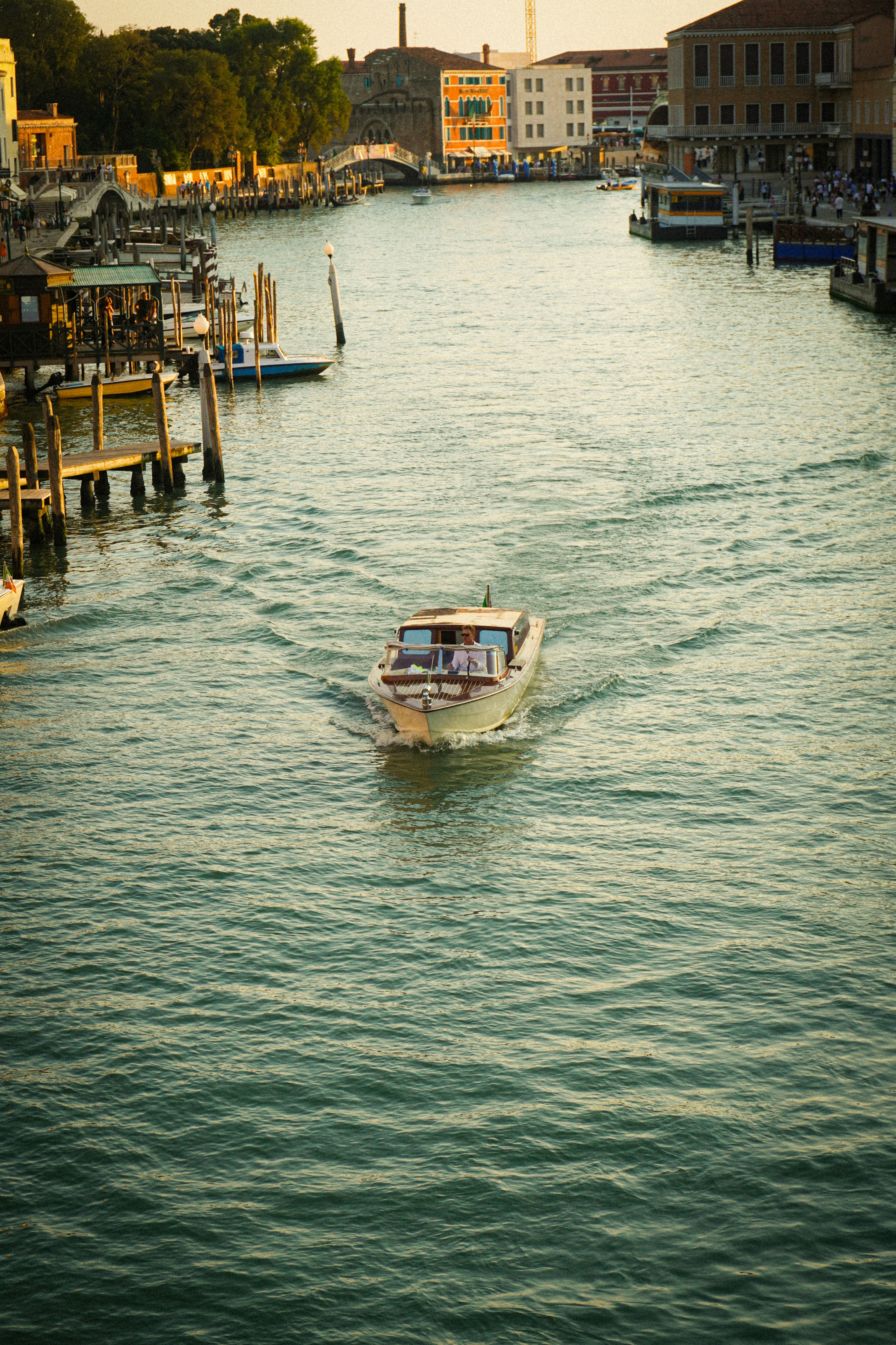 Toward the Bridge: A Lone Boat in a Sunlit Venetian Channel