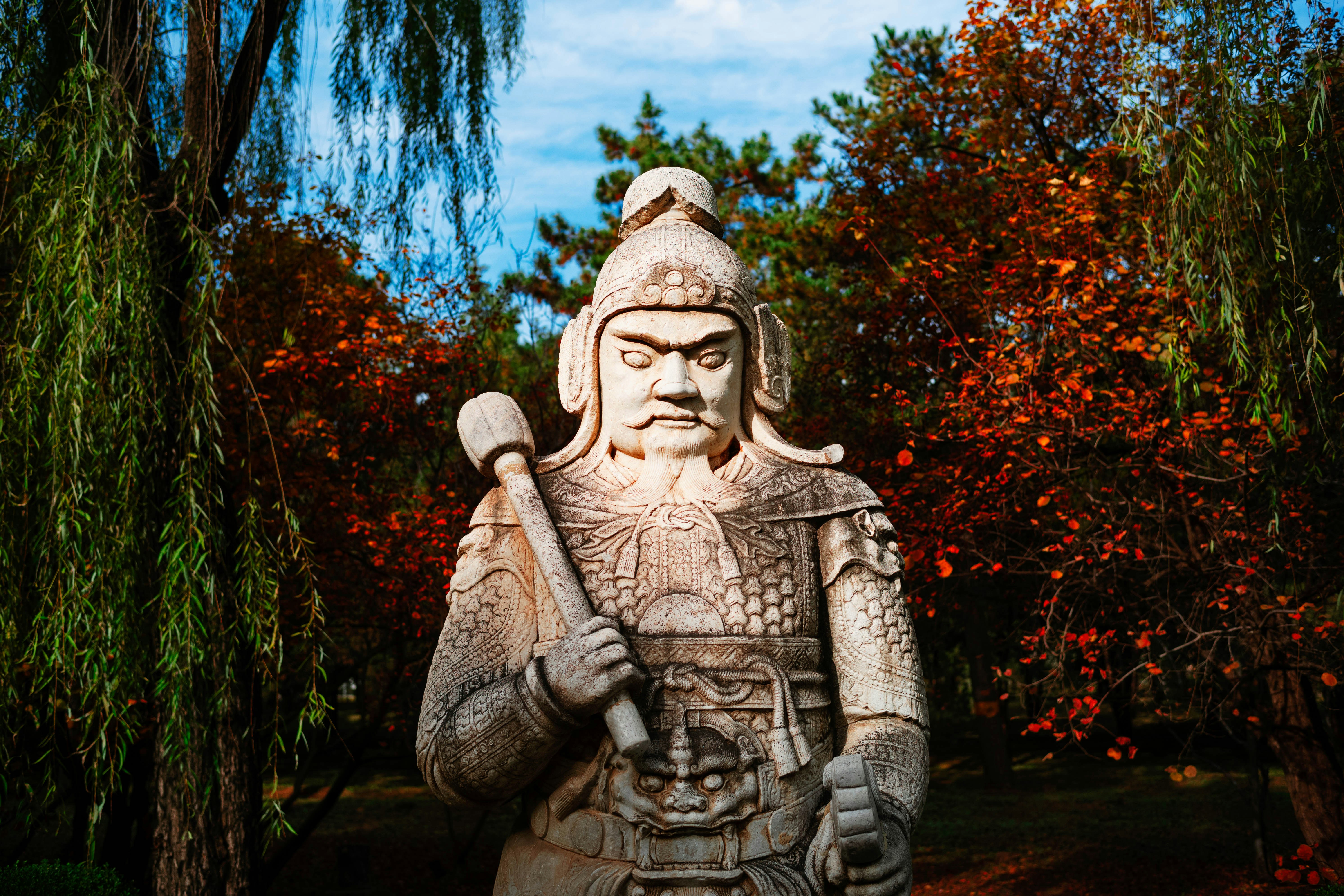 Autumn Sentinel: A Stone Warrior Amid Red Leaves