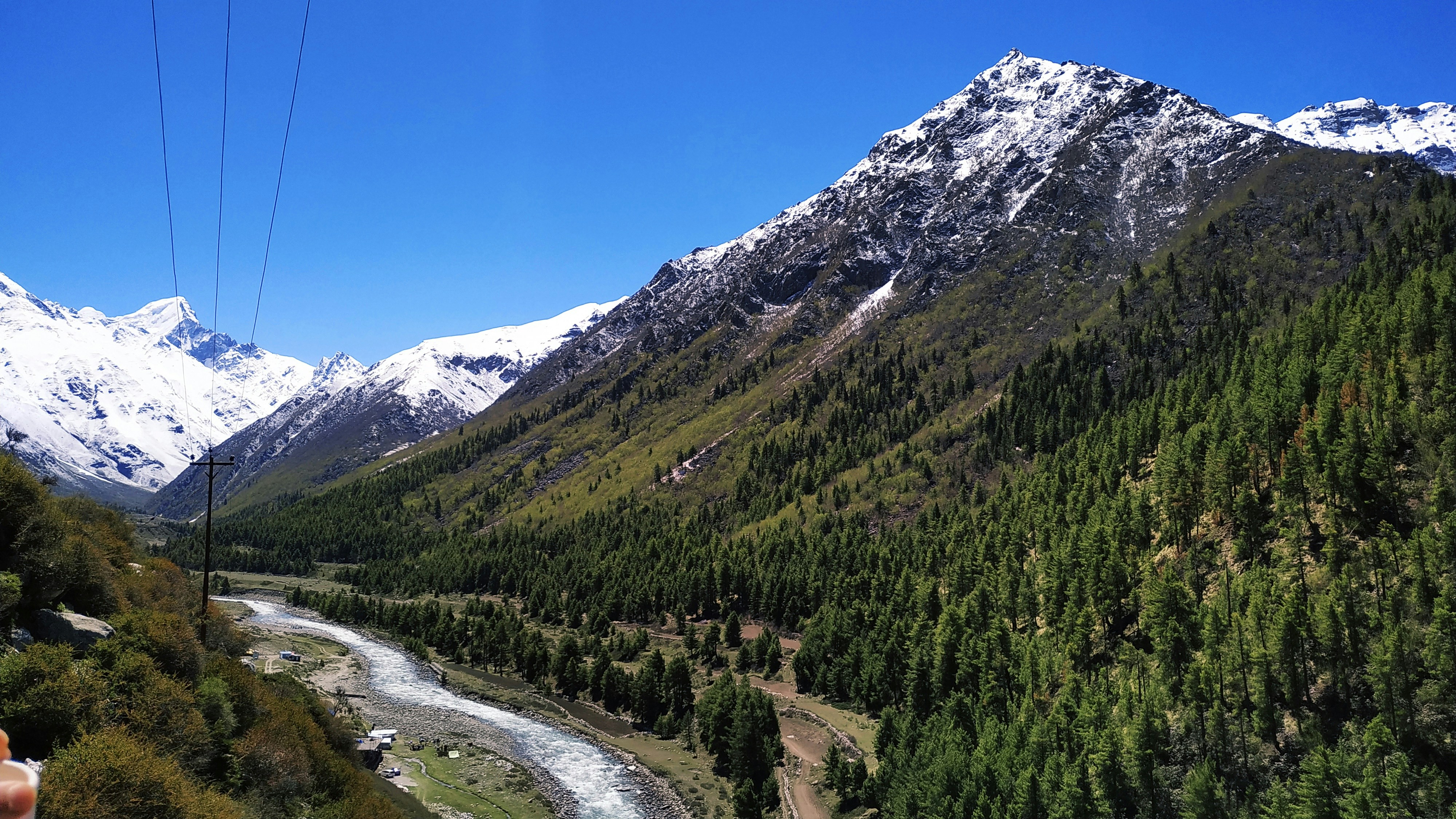 Alpine Ribbon: Snow-Capped Peaks Framing a Pine-Lined Valley