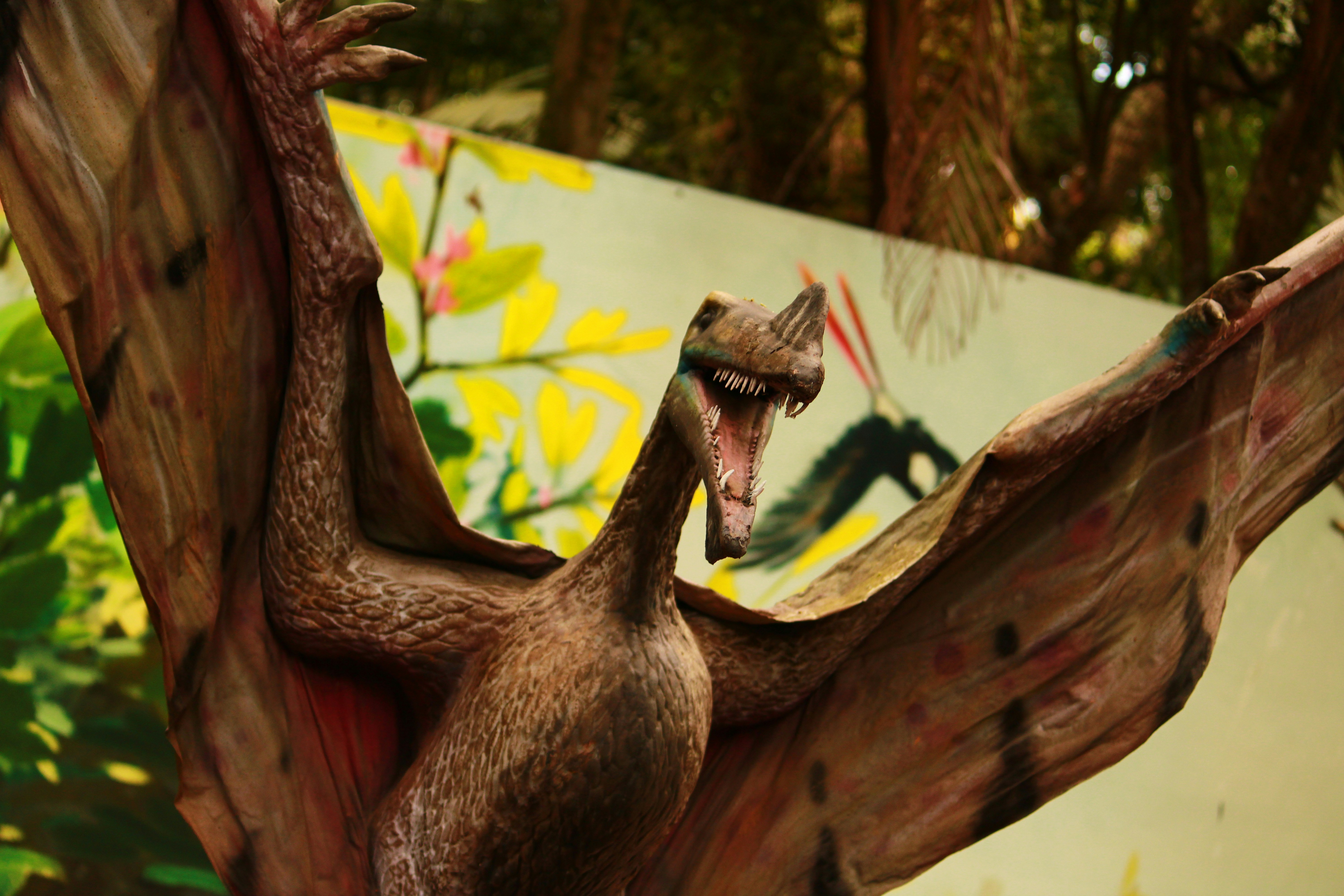 Winged Dino Sentinel: Sunlit Statue Against a Graffiti Backdrop