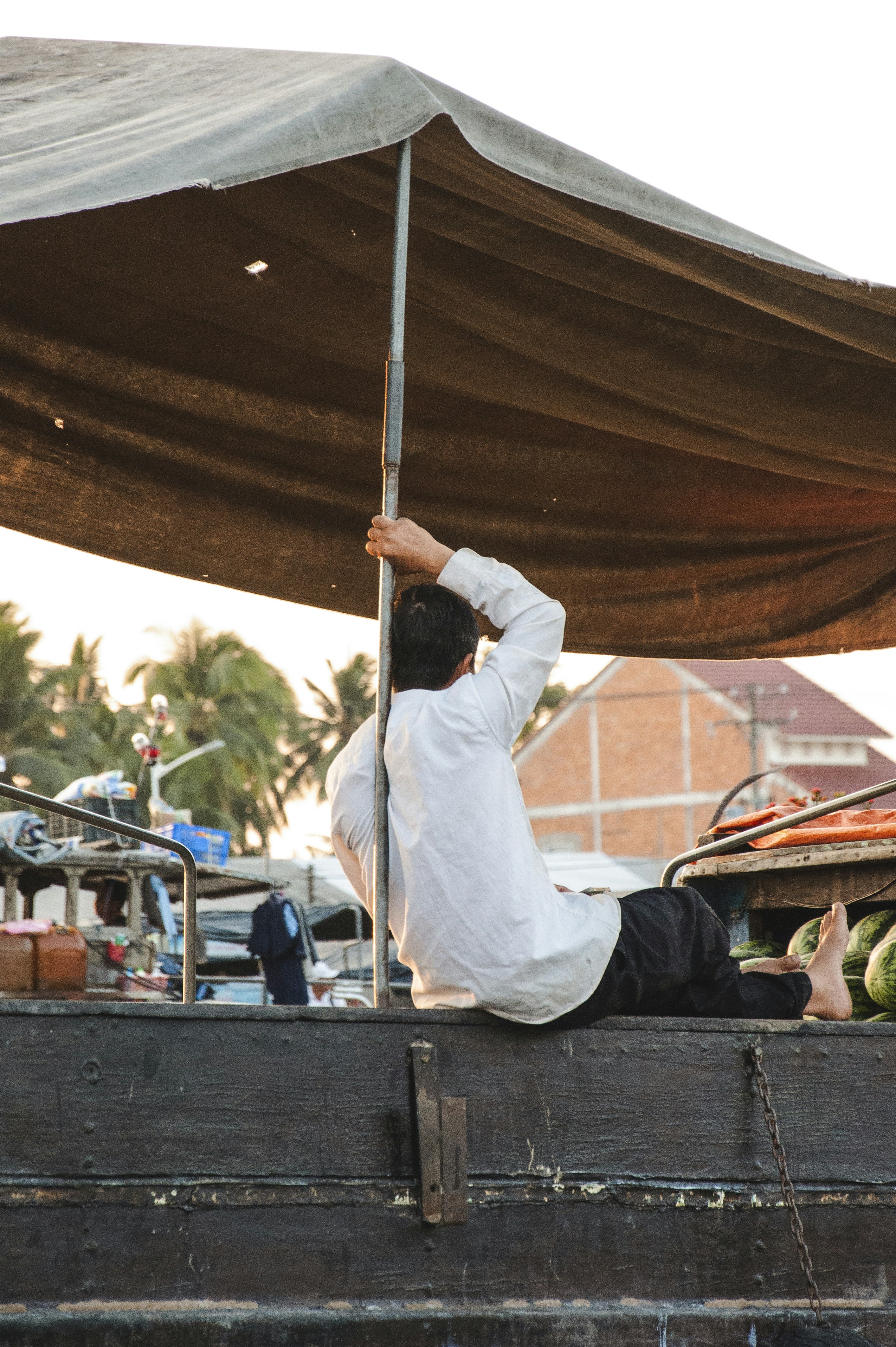 Under the Shelter: Man Reaches for the Shade from a Weathered Caravan