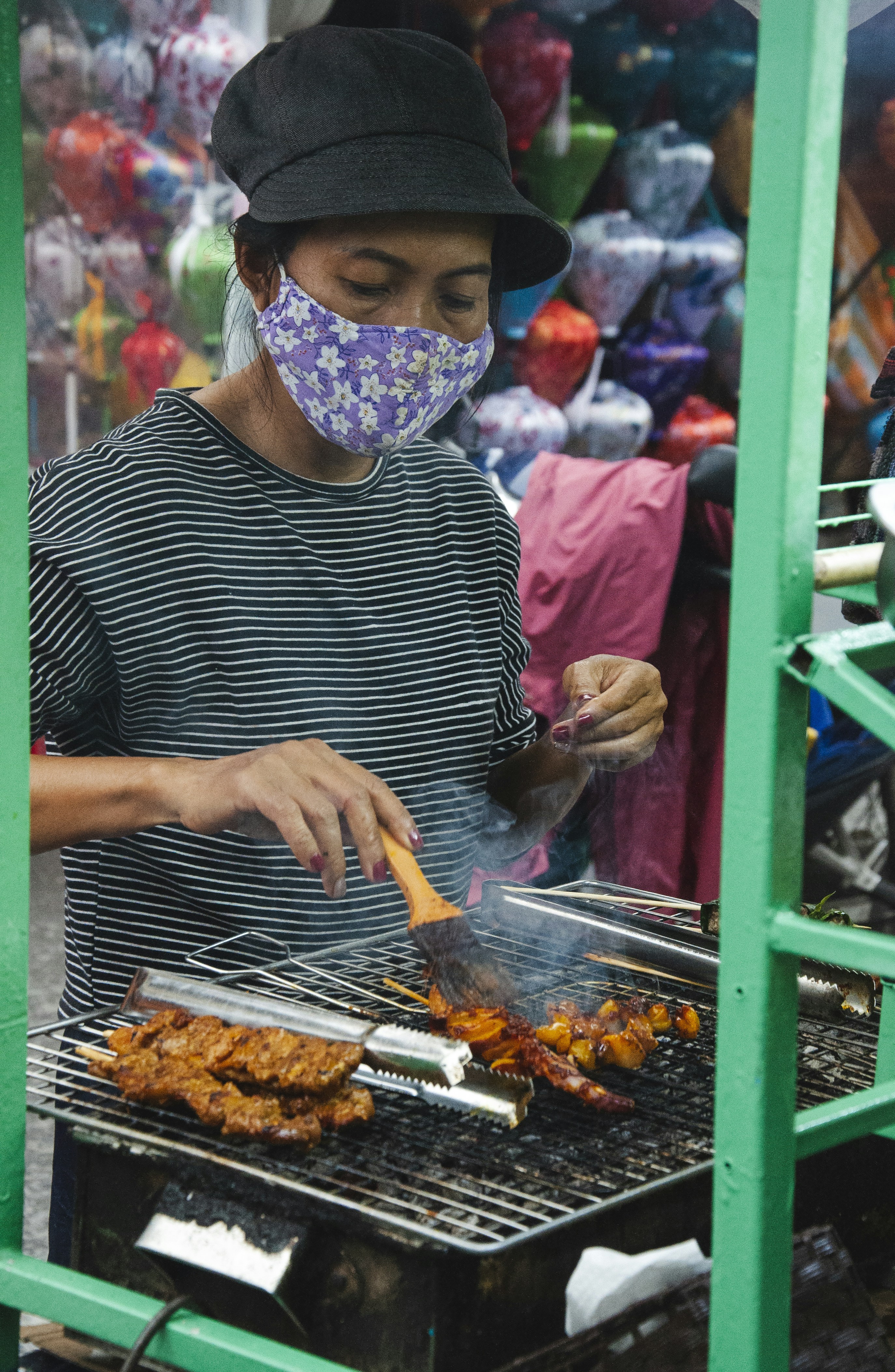 Street vendor grilling skewers at a bustling market stall.