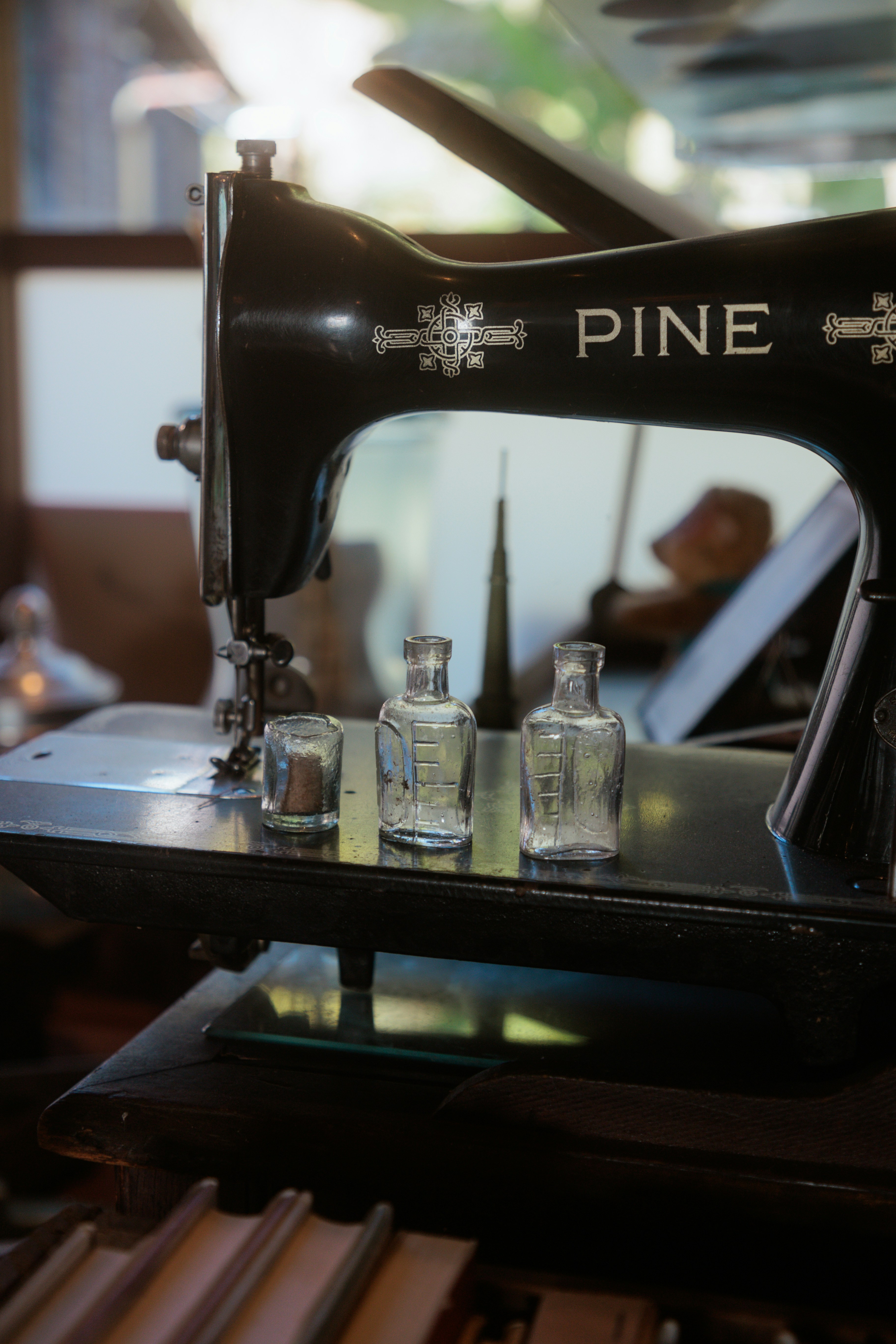 Pine on the Plate: A Vintage Sewing Machine Framed by Glass Bottles